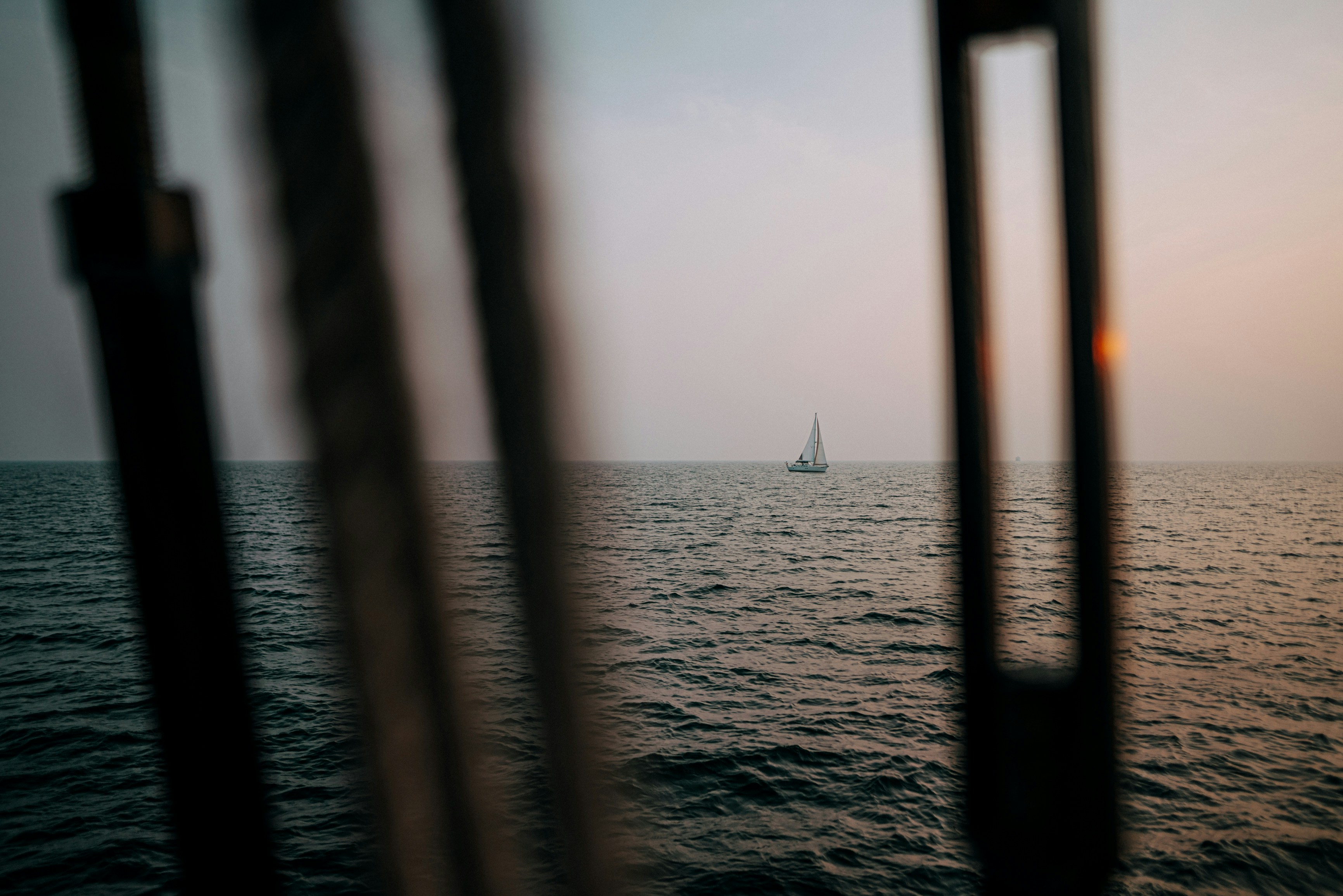 A sailboat in the distance on a body of water photo – Free Boat Image ...