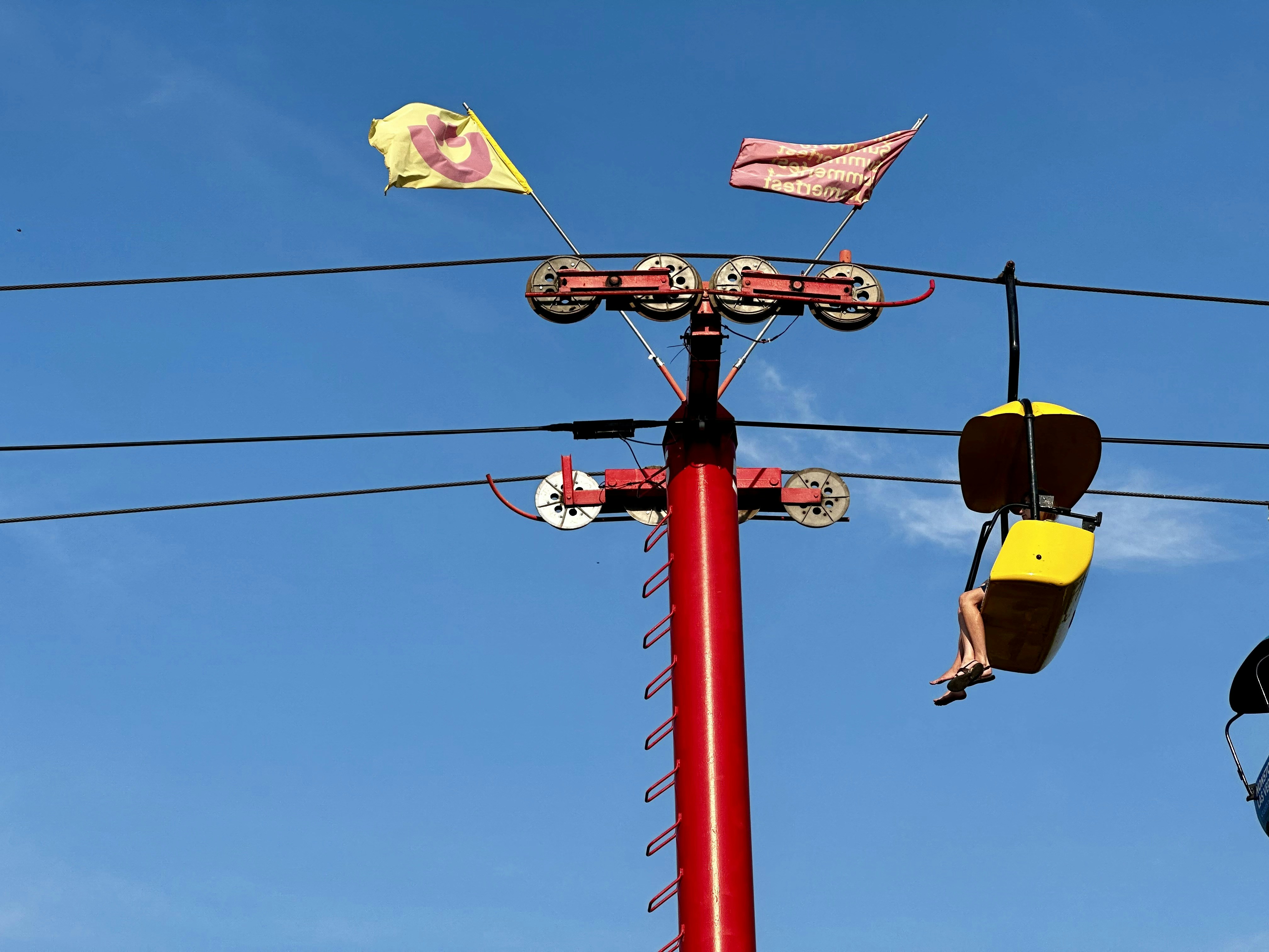 Skyline Lift: A Red Pole with Floating Cabins Against a Clear Blue