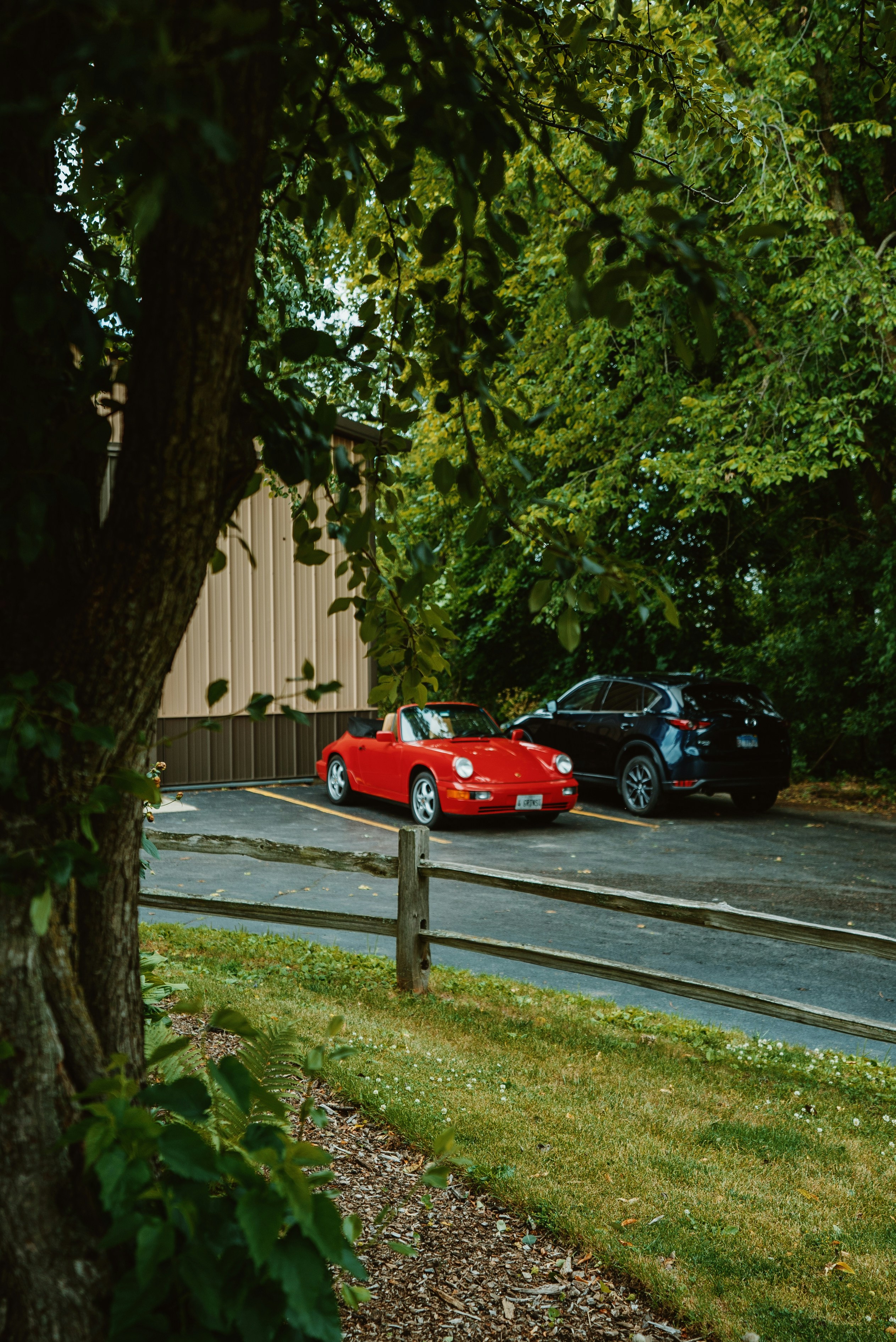 Crimson Convertible Resting in the Shade by a Parked SUV