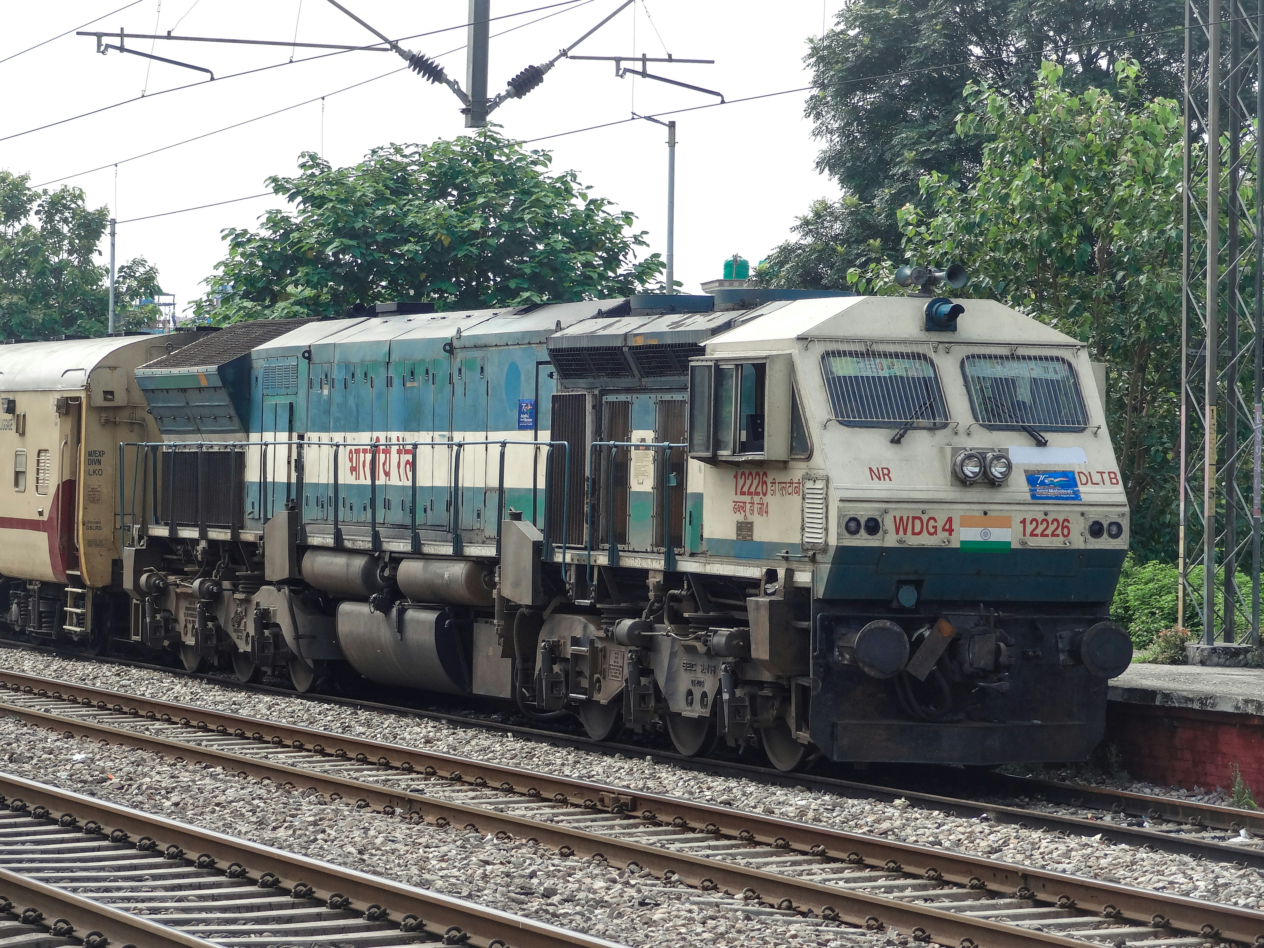 A train traveling down train tracks next to a forest photo – Free ...