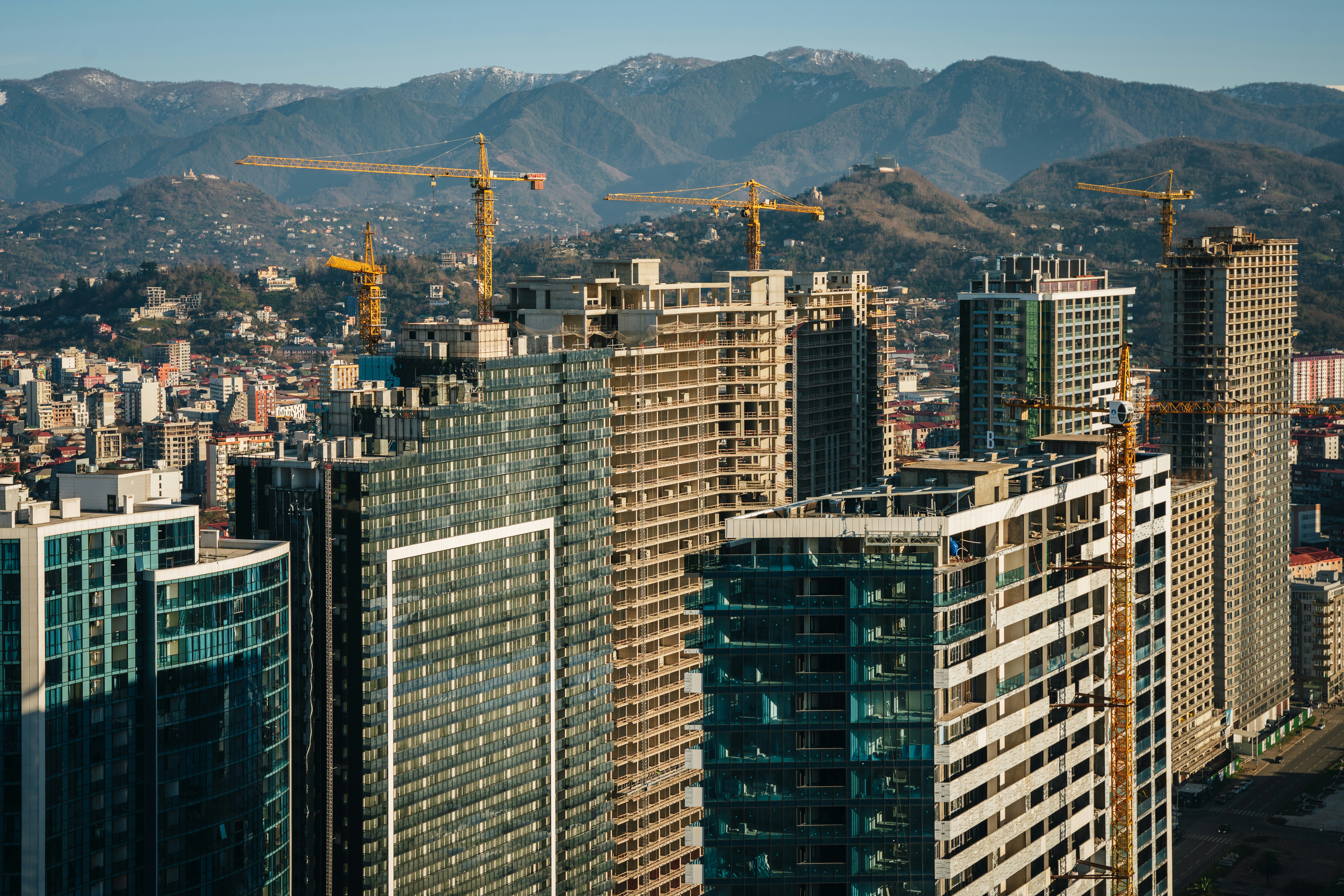 Cranes and Glass Towers: A City Rising Toward the Mountains