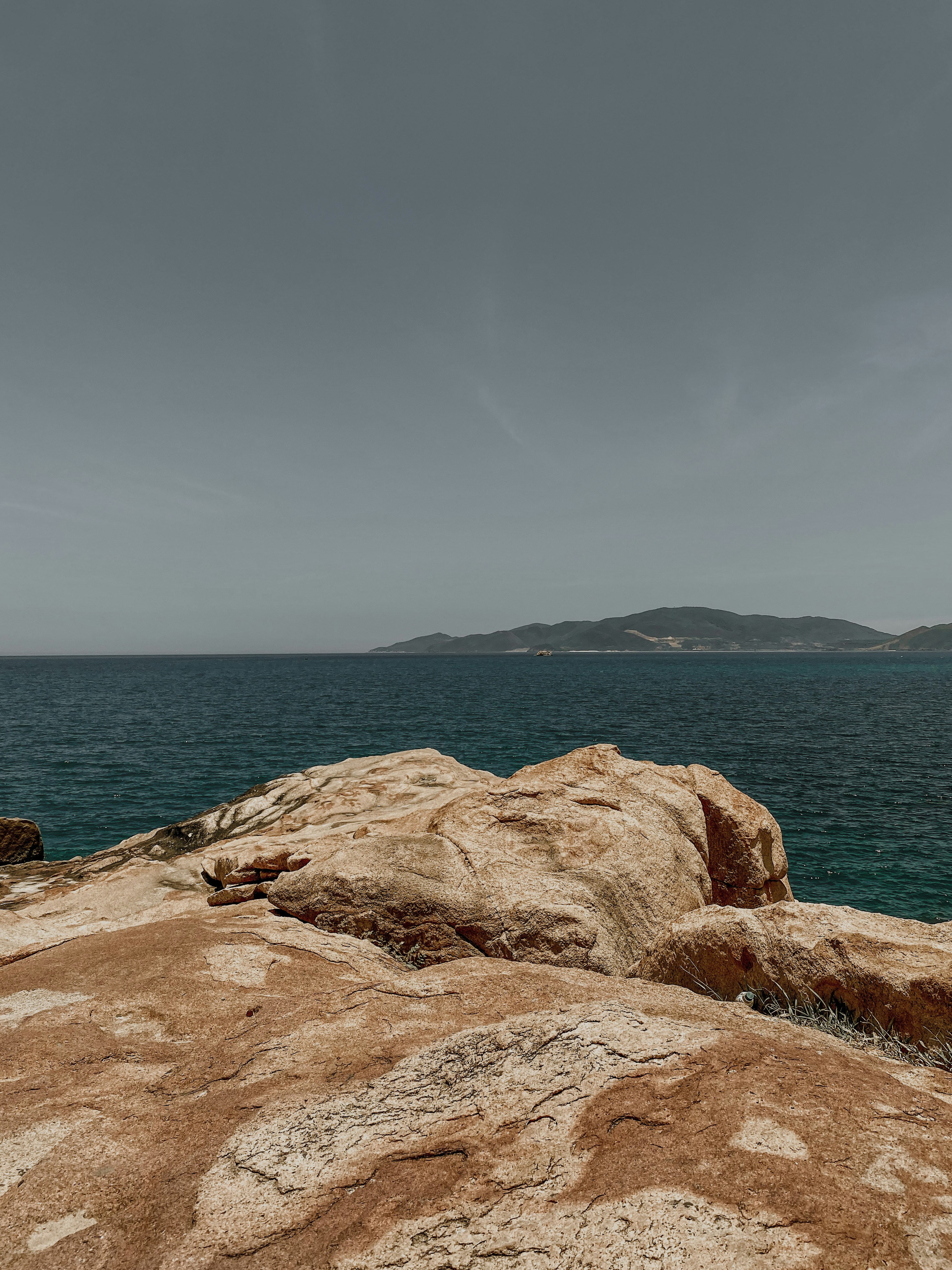 A rock outcropping with a body of water in the background photo – Free ...