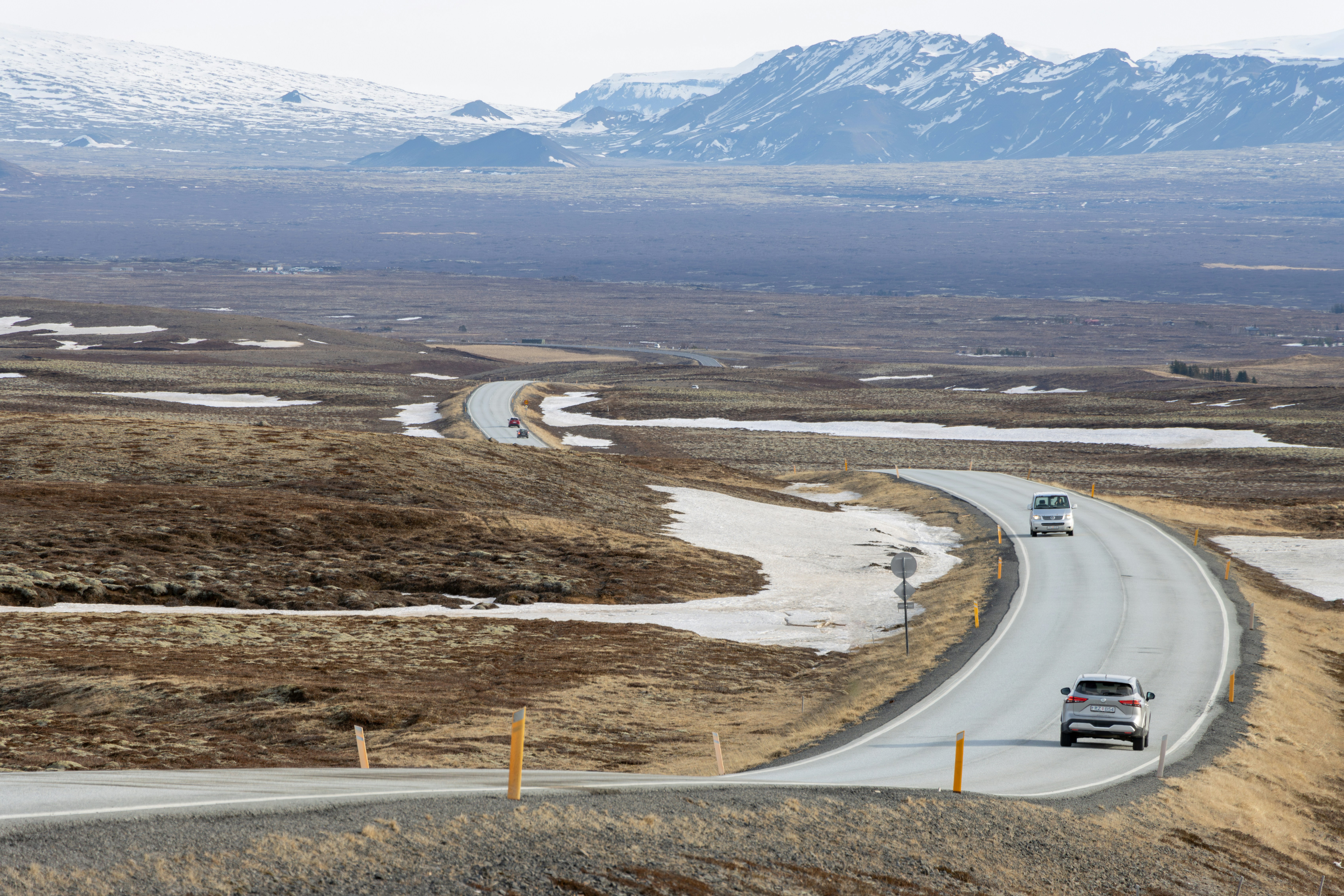 Serpentine Road Through a Windswept Plain Toward Snow-Capped Peaks