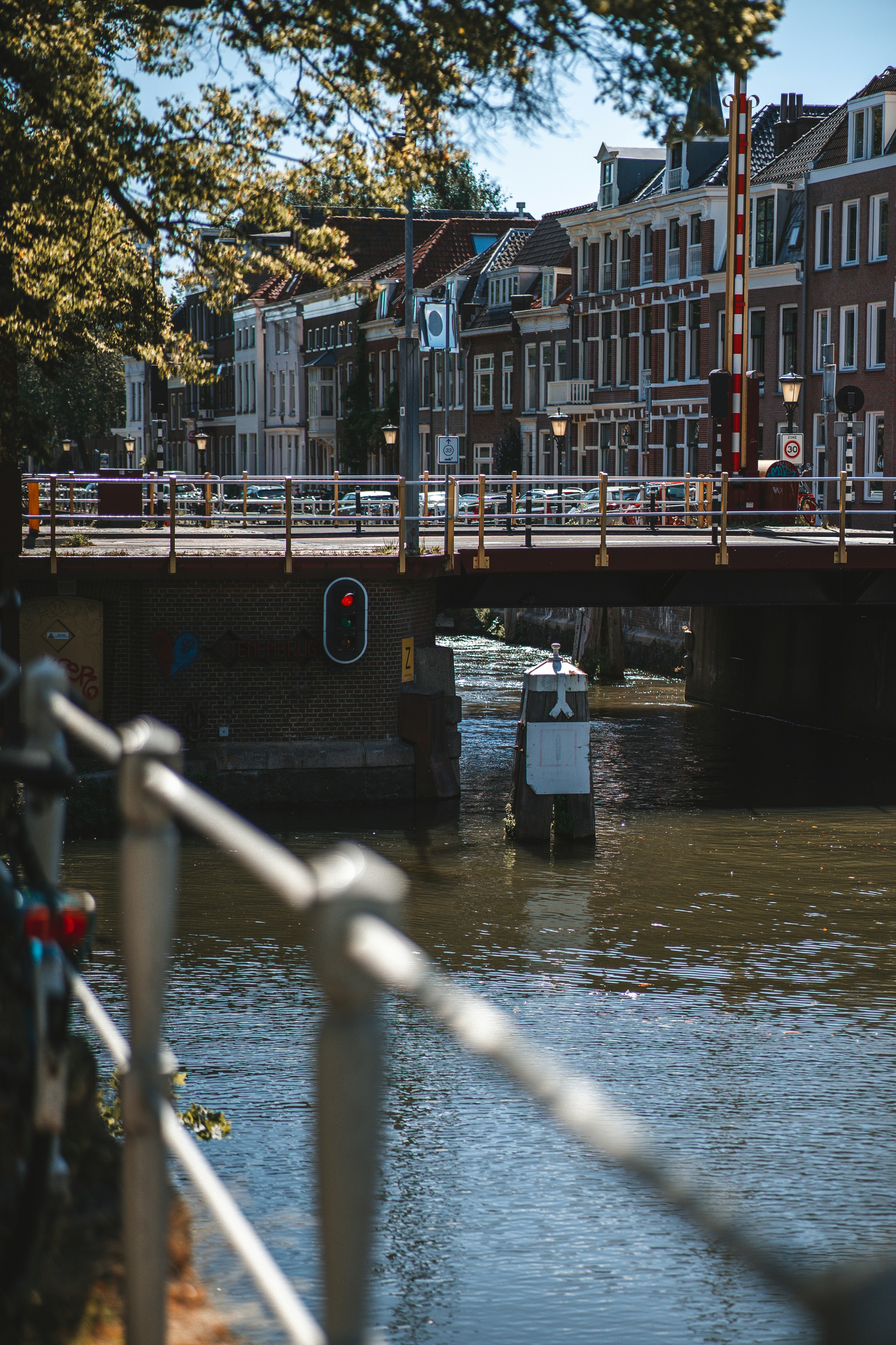 Sunlit Dutch Canal Bridge: Brick Facades, Rails, and a Quiet Boat