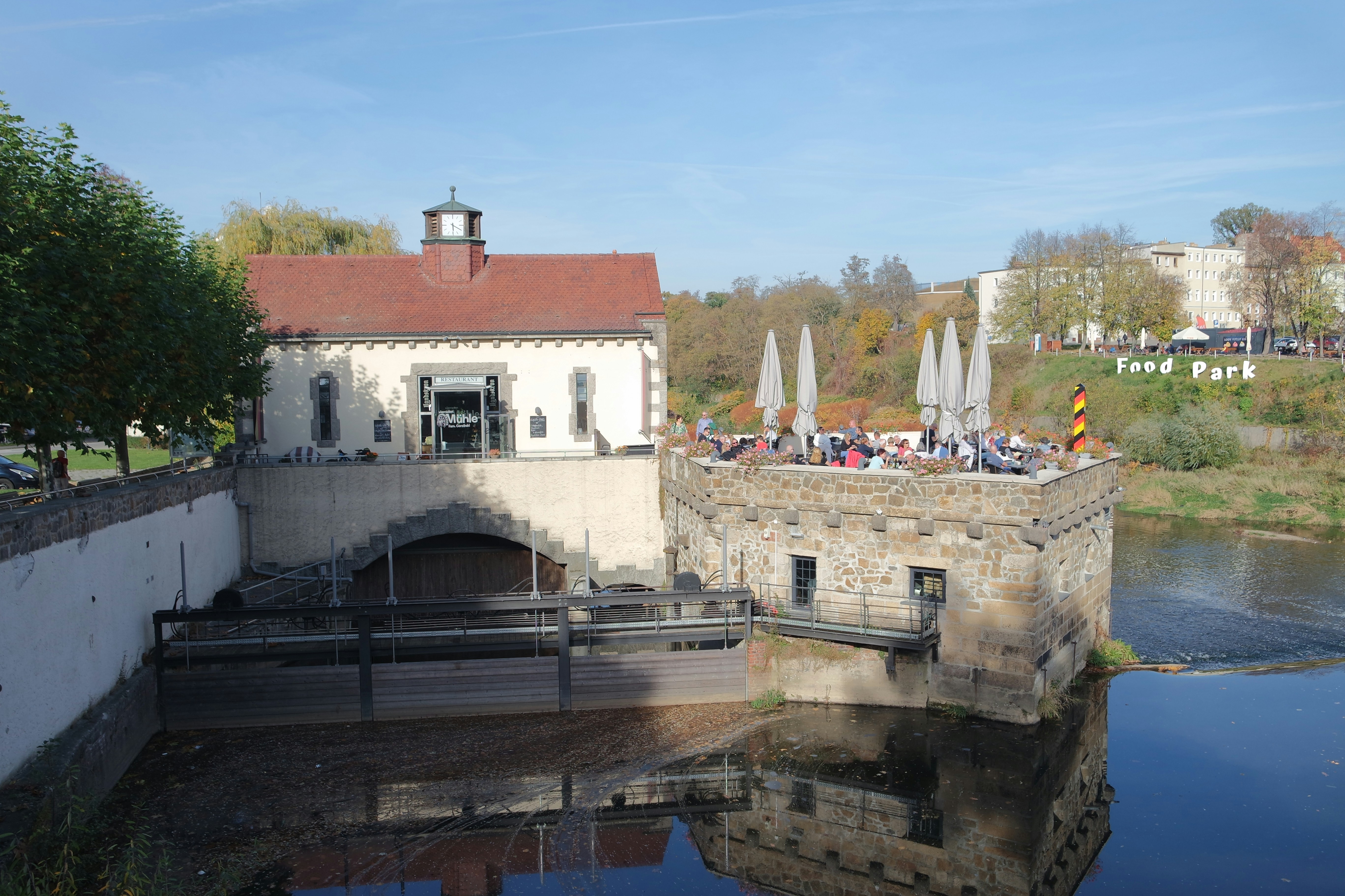 Riverside Gatehouse and Terrace: Sunlit Pause by the Water