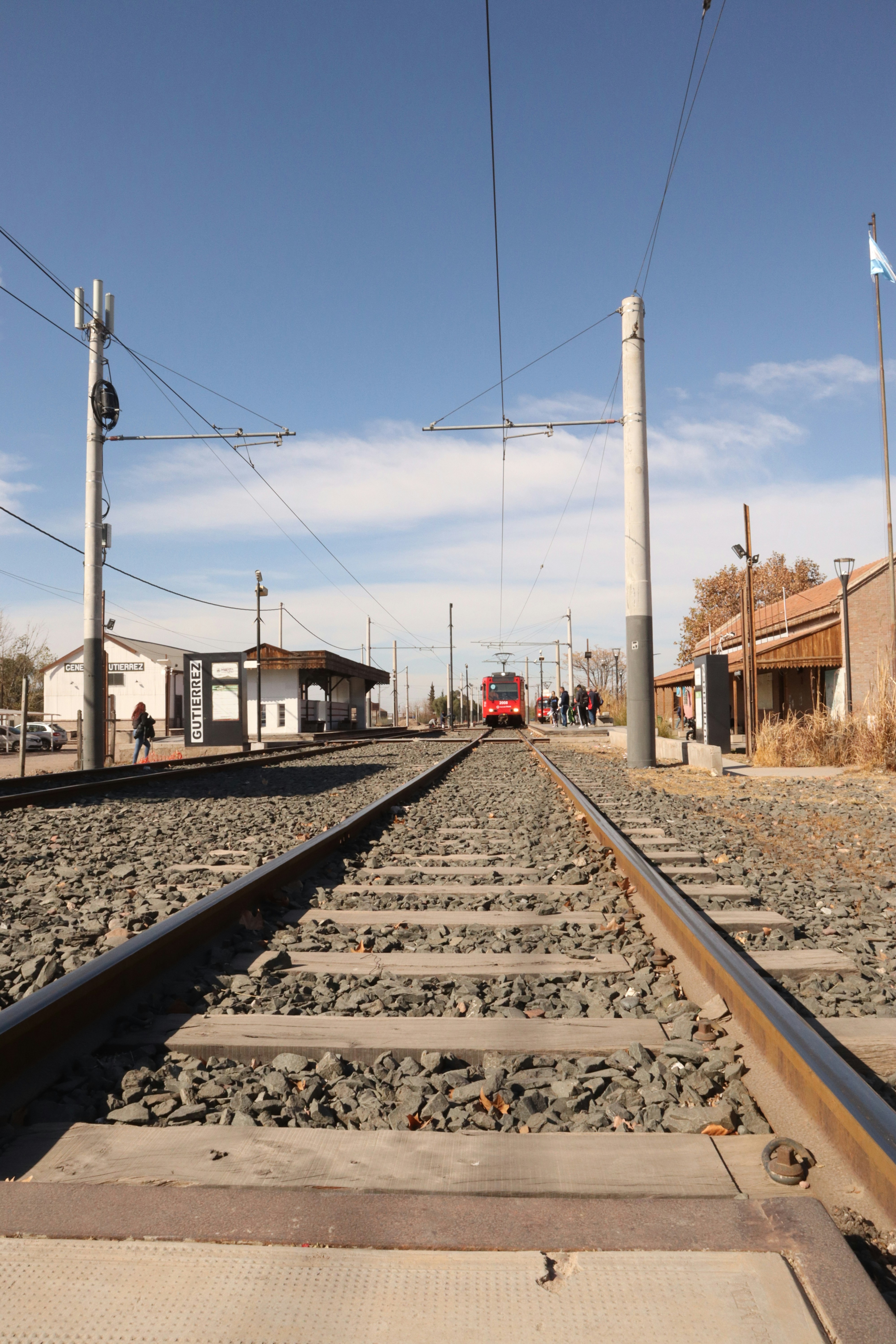 A red train traveling down train tracks next to a building photo – Free ...