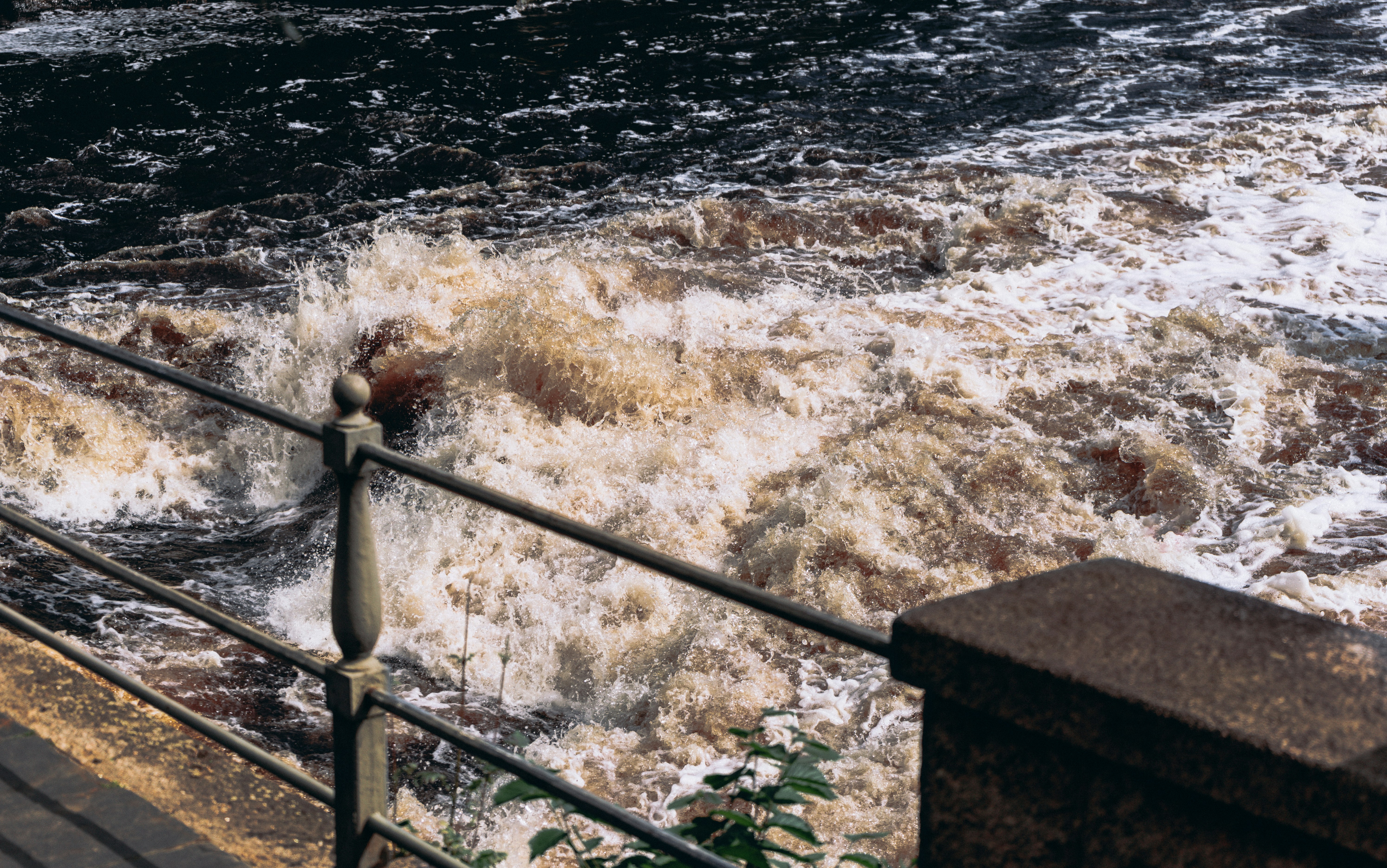 Foam and Ironwork: Rapids Fracture Along a Riverside Walk