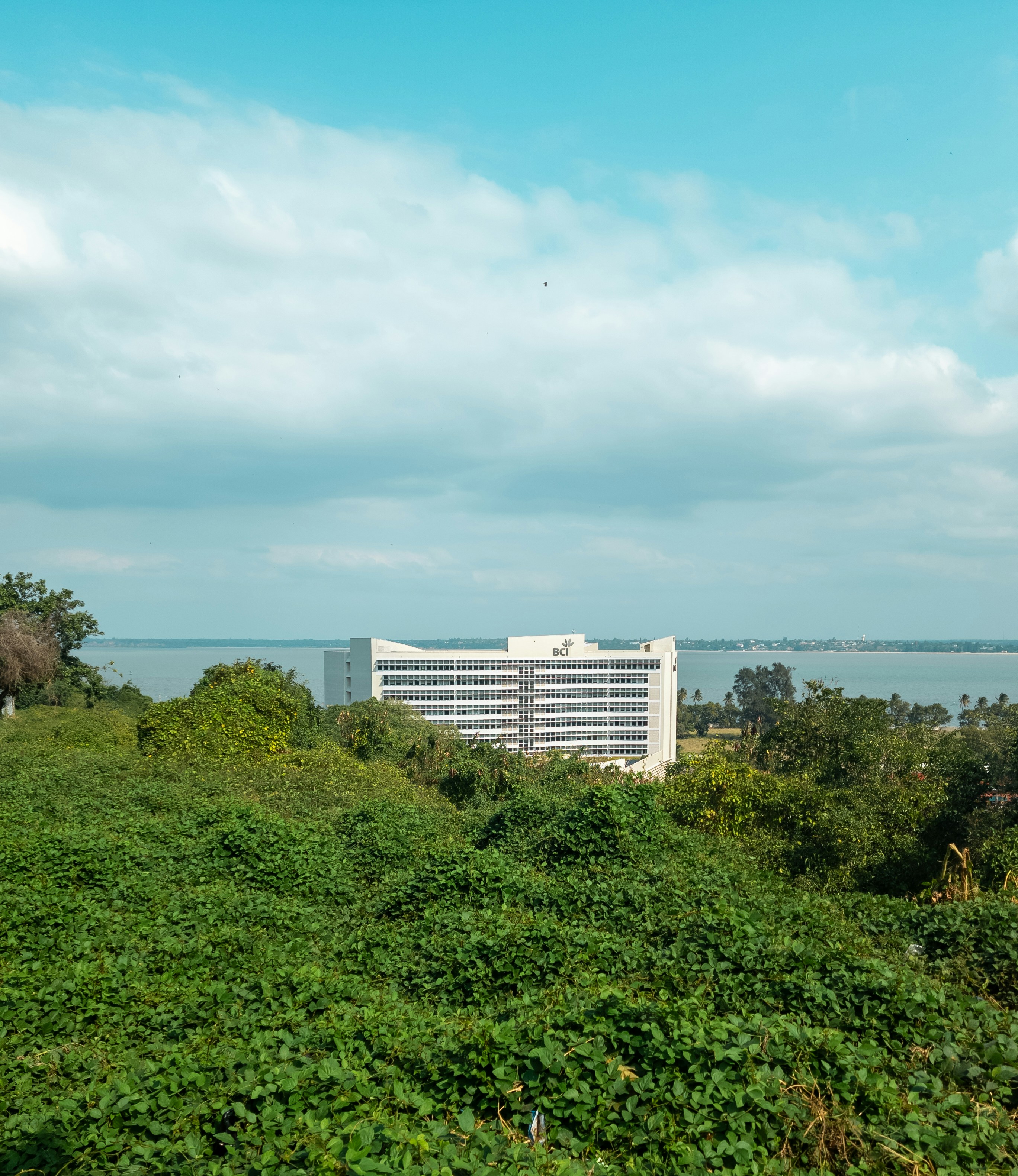 A large white building sitting on top of a lush green hillside photo ...