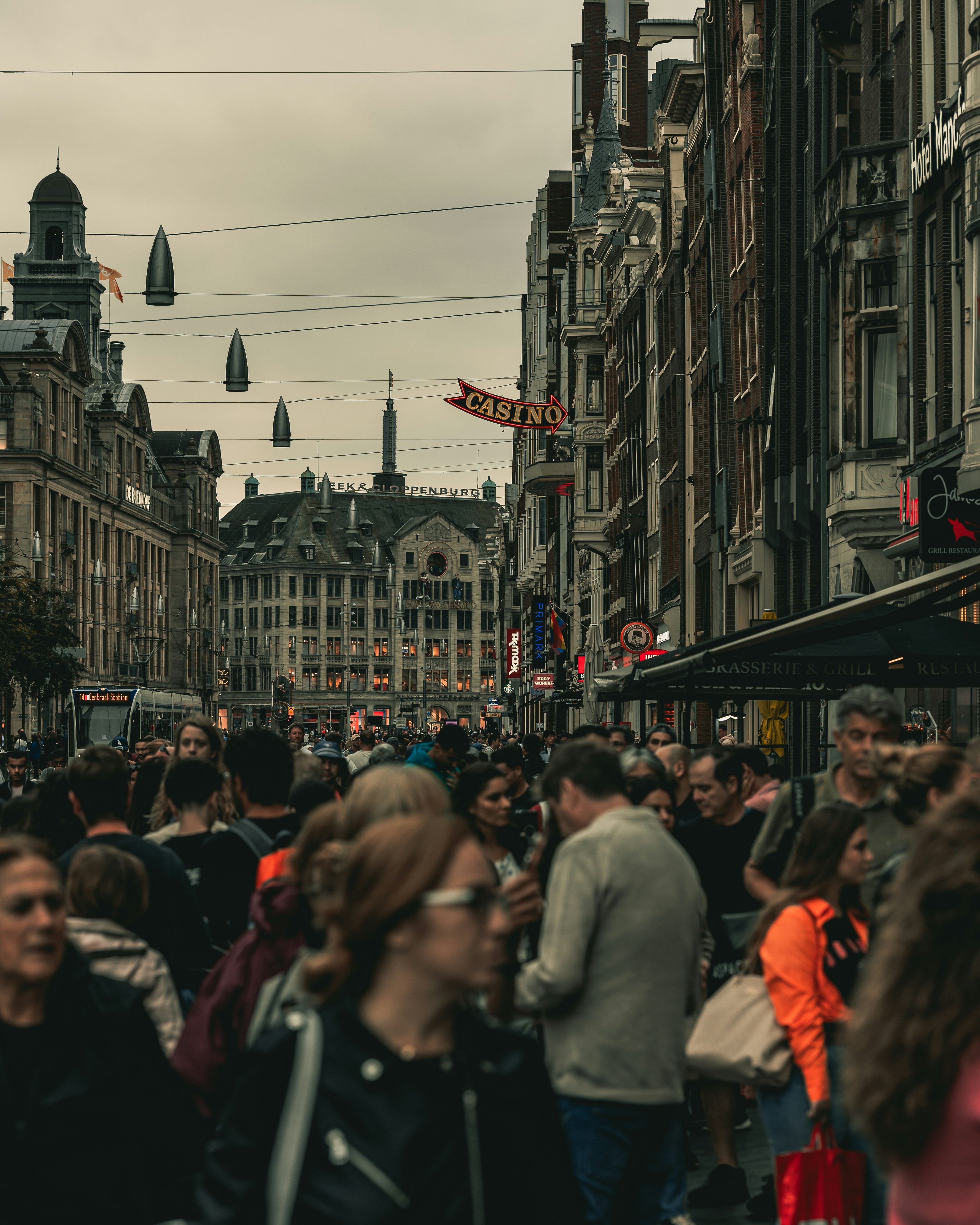 A crowd of people walking down a street next to tall buildings photo ...