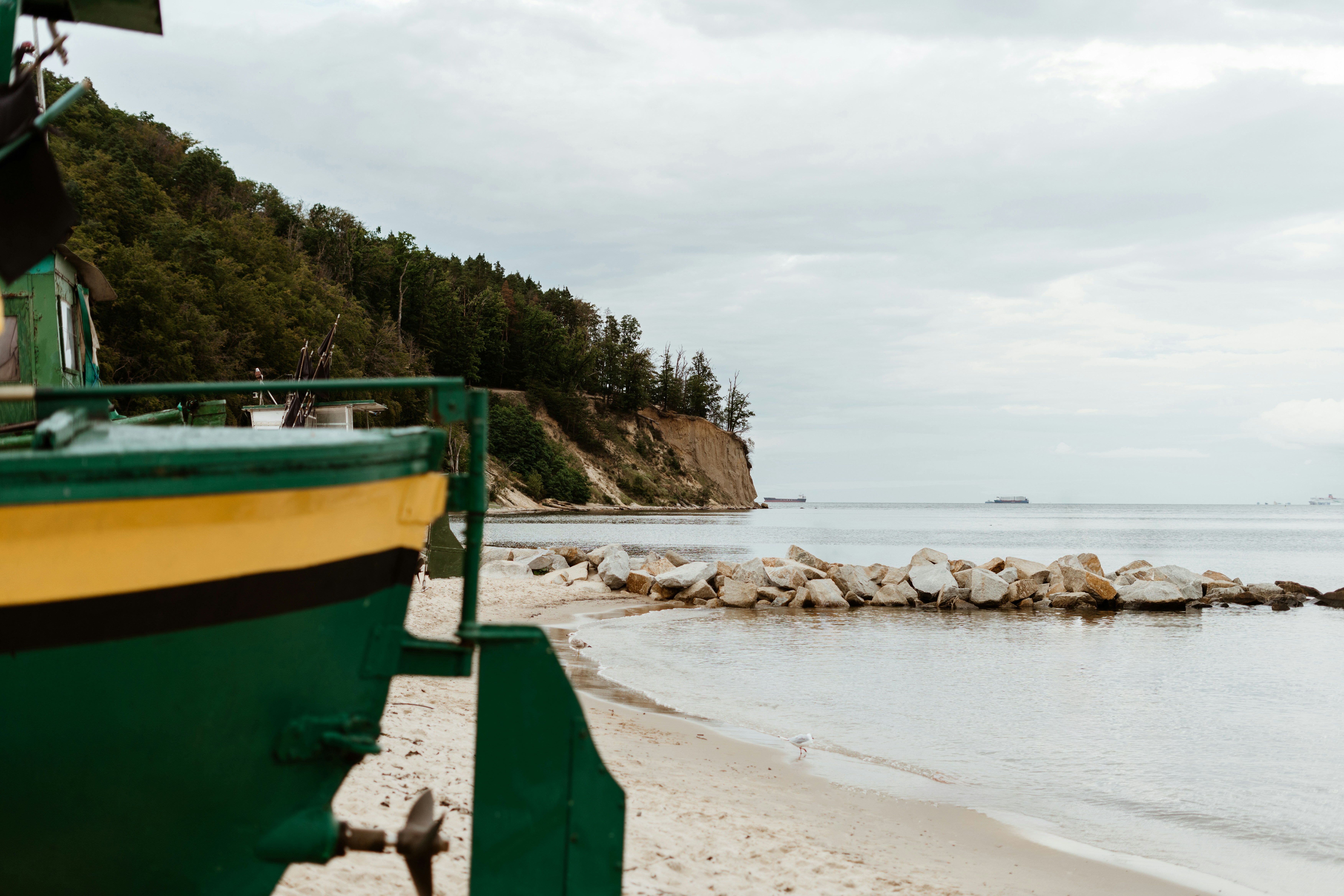 Green Hull at the Quiet Edge: A Coastal Scene of Boats and Calm Water