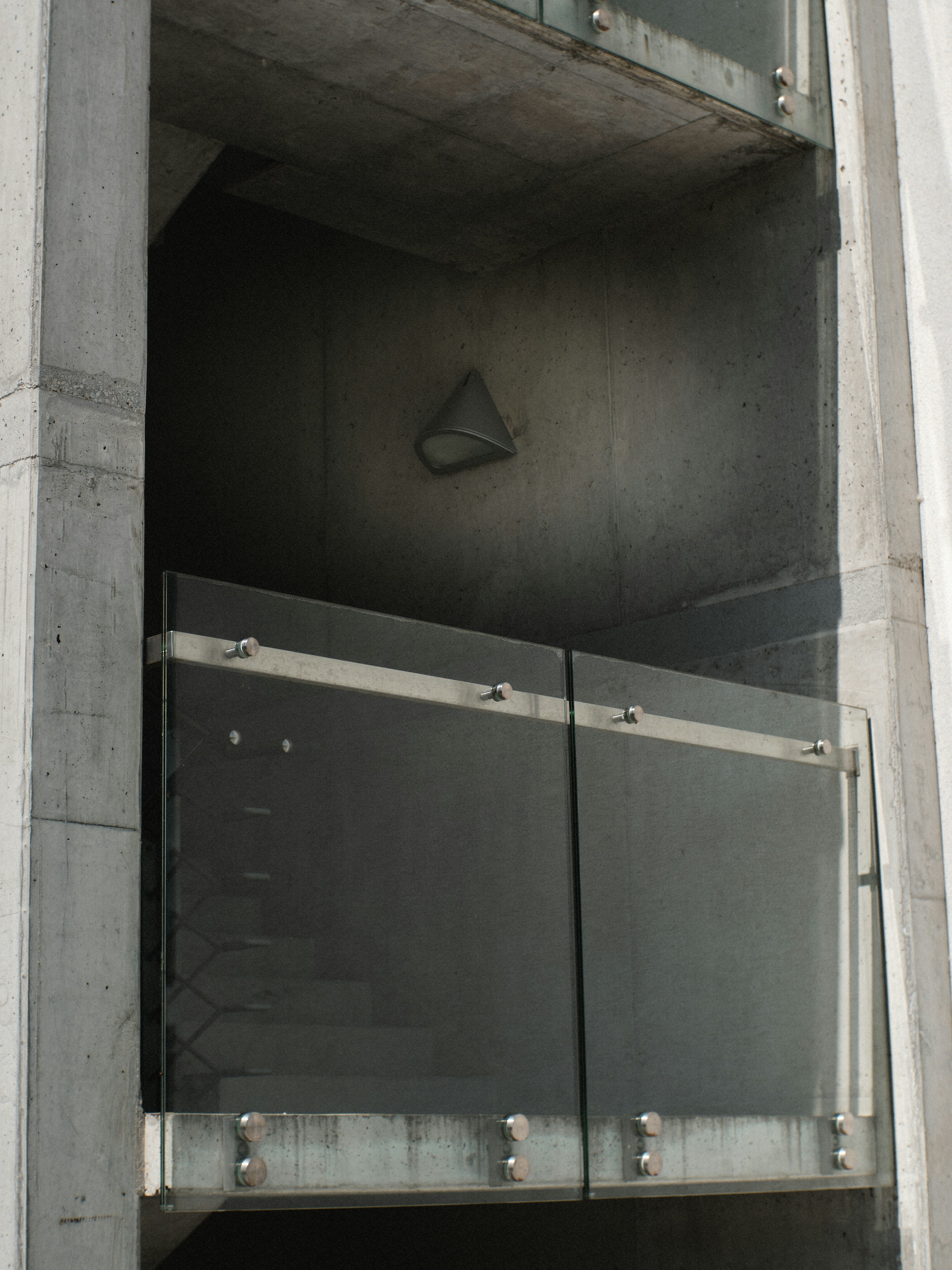 Quiet Nook Behind Glass Rail in a Concrete Atrium
