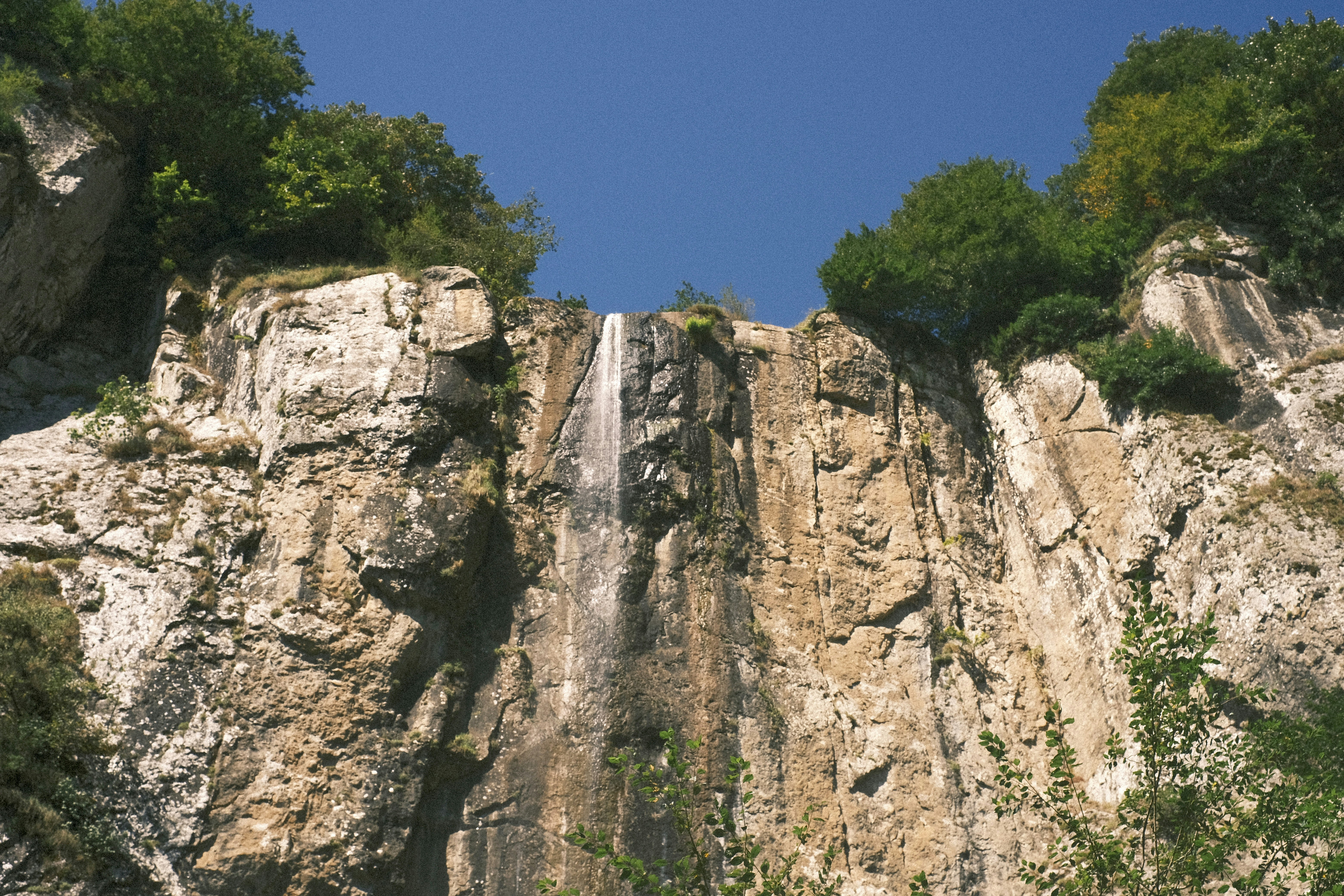 A very tall waterfall in the middle of a forest photo – Free Nature ...