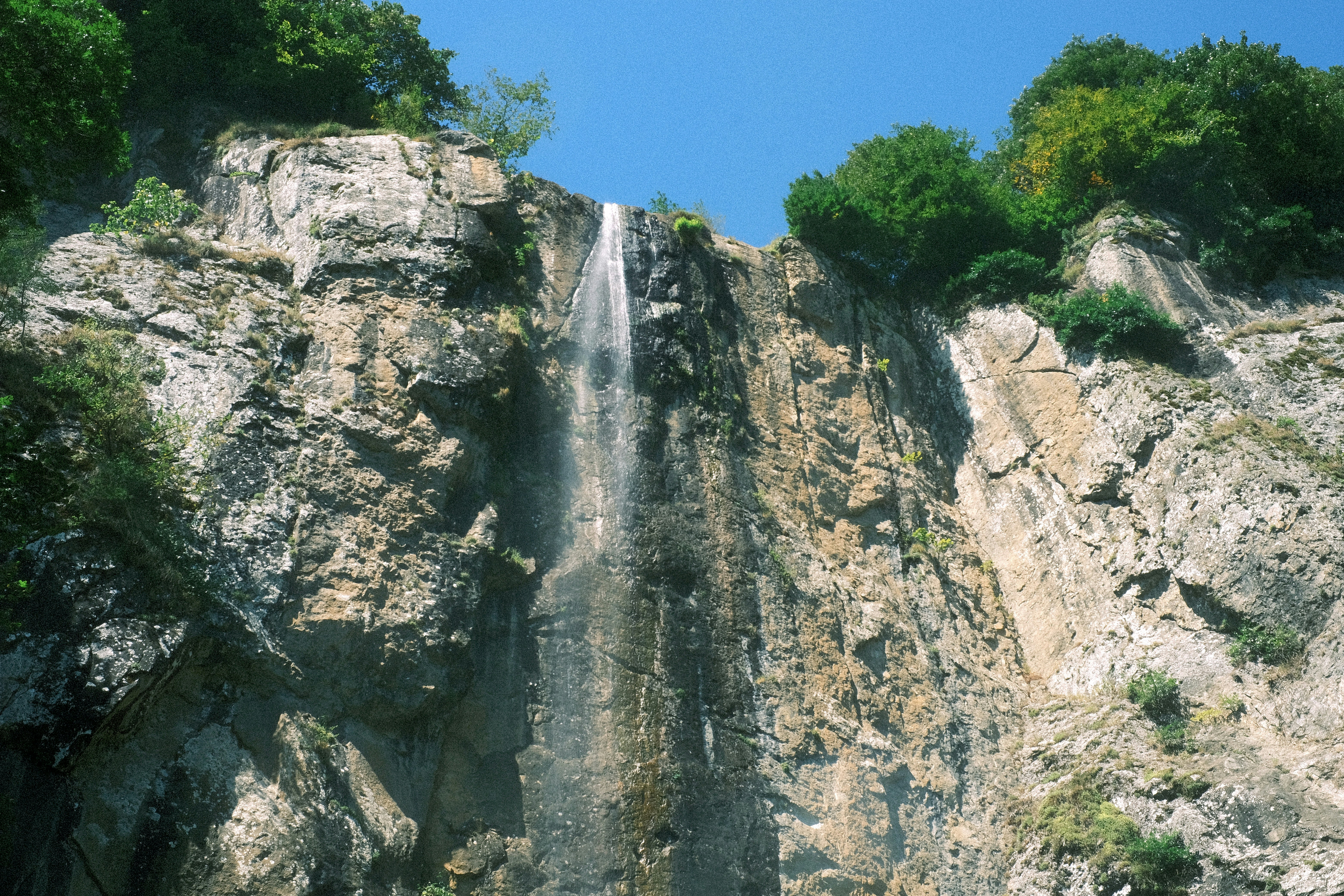 A very tall waterfall in the middle of a forest photo – Free Nature ...