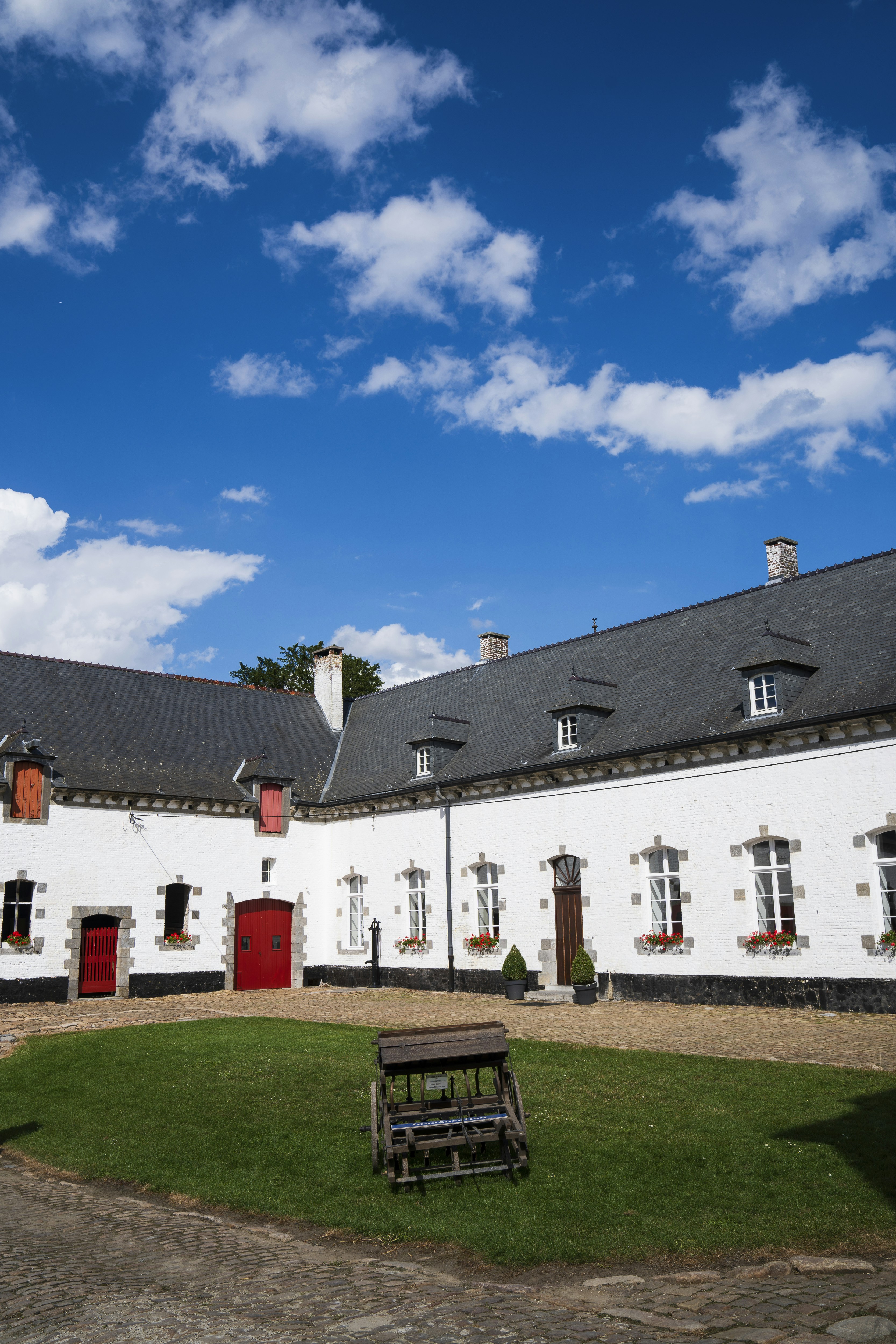 Crimson Doors, White Facades: A Sunlit Courtyard Under Azure Sky