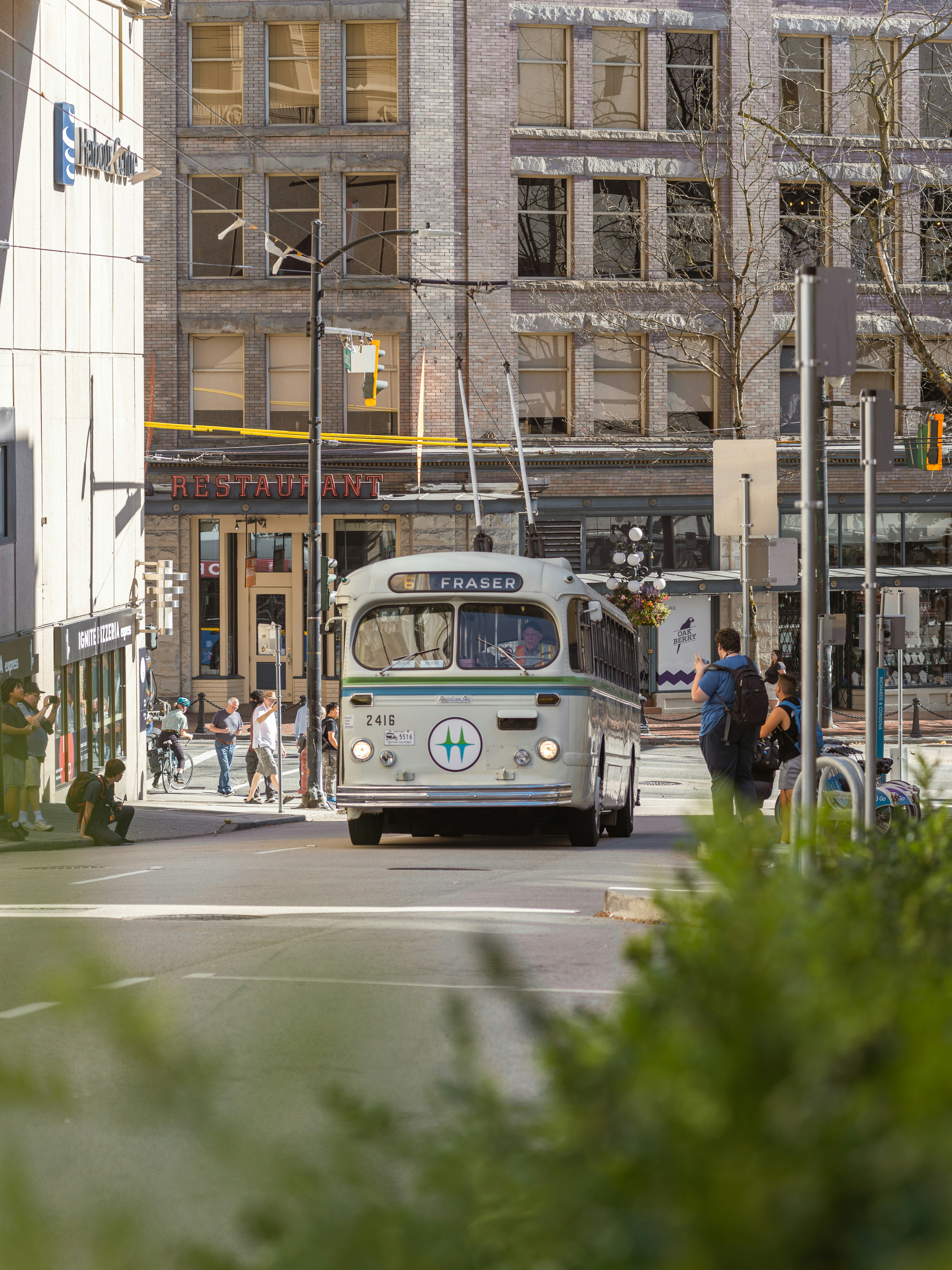 A white bus driving down a street next to tall buildings photo – Free ...