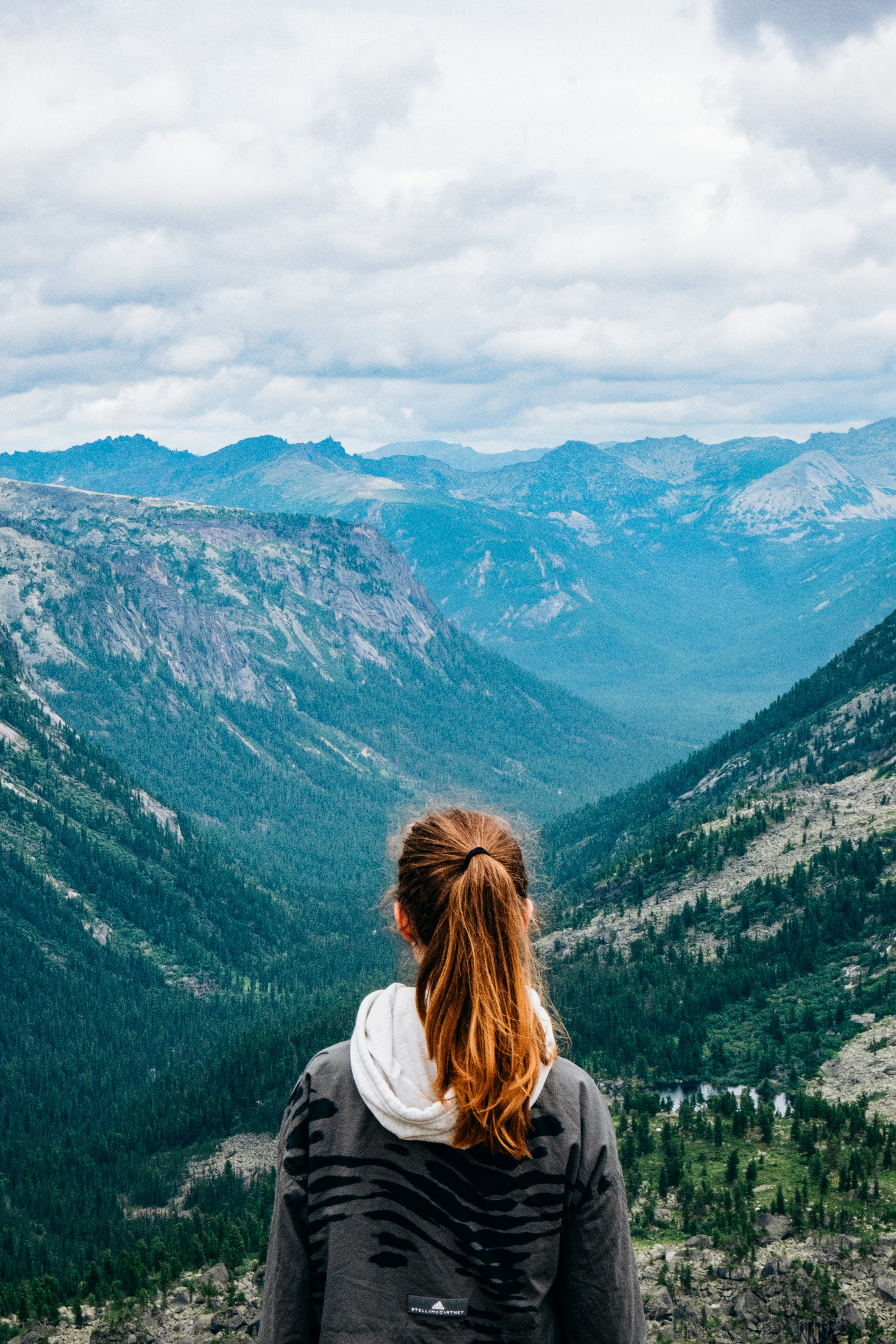 A woman standing on top of a mountain overlooking a valley photo – Free ...