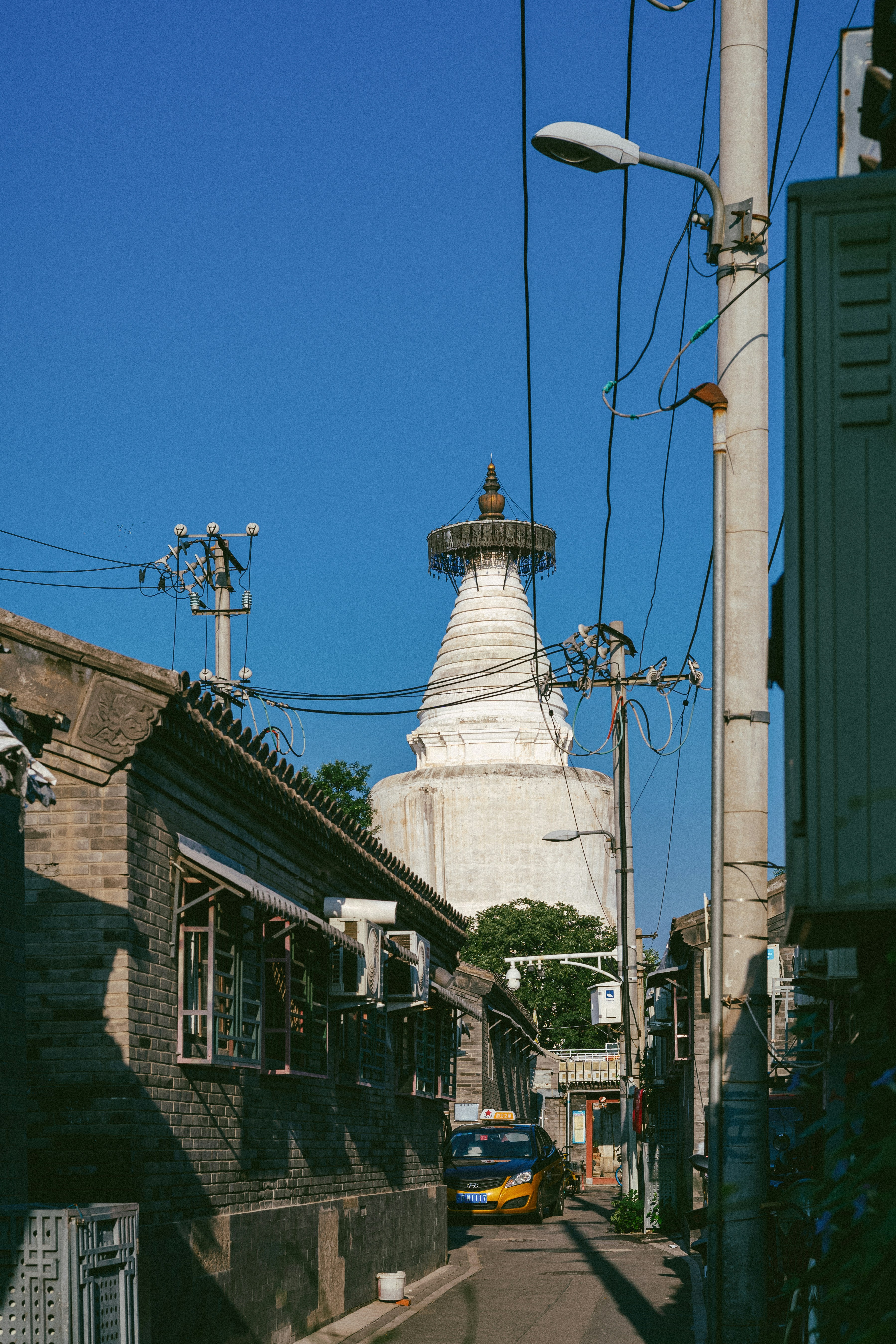 Electric Veins and a White Spire: An Alley’s Quiet Approach to a Buddhist Monument