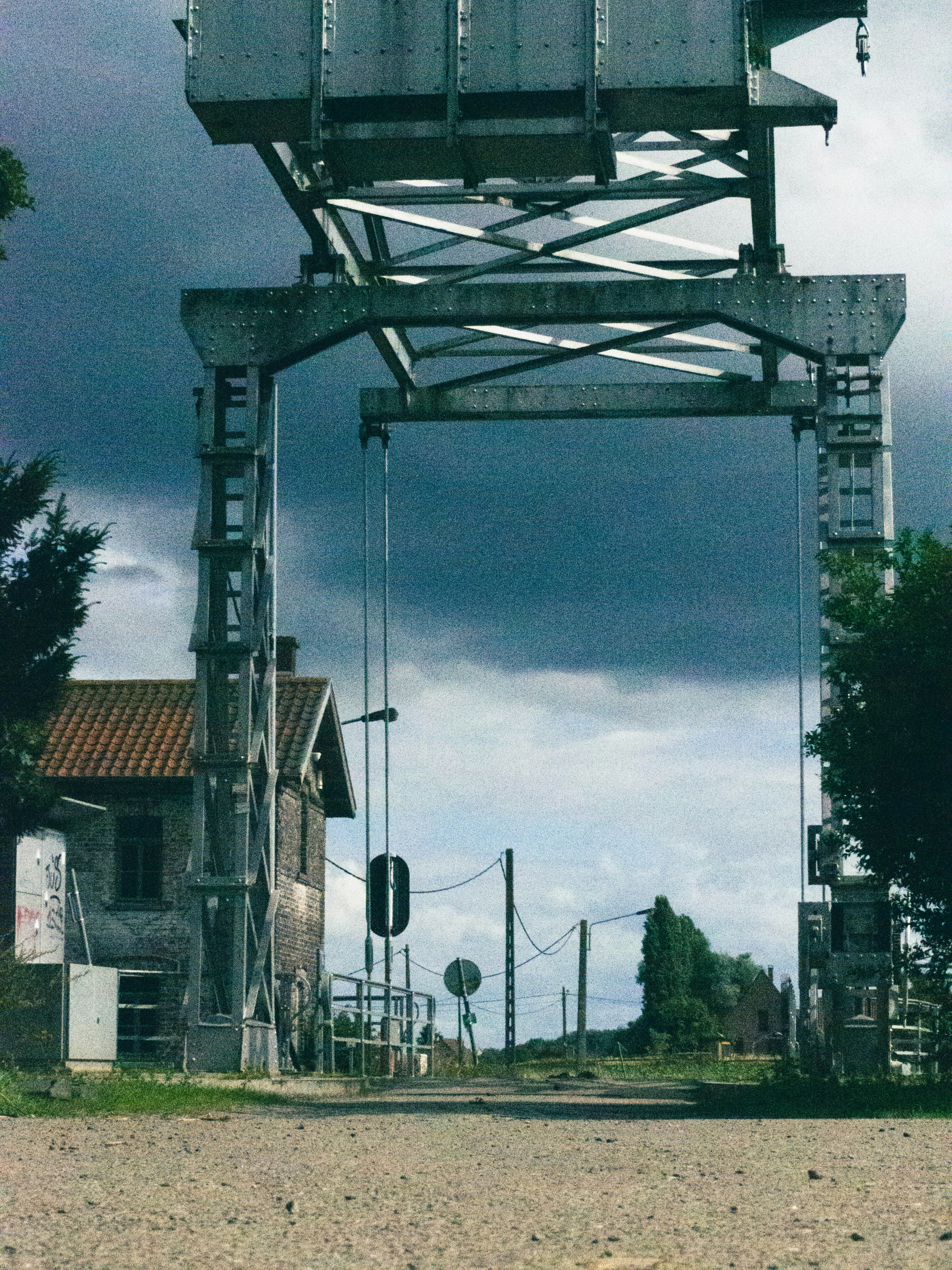 Crossed Girders, Quiet Tracks: A Rural Gateway under Tempest Skies