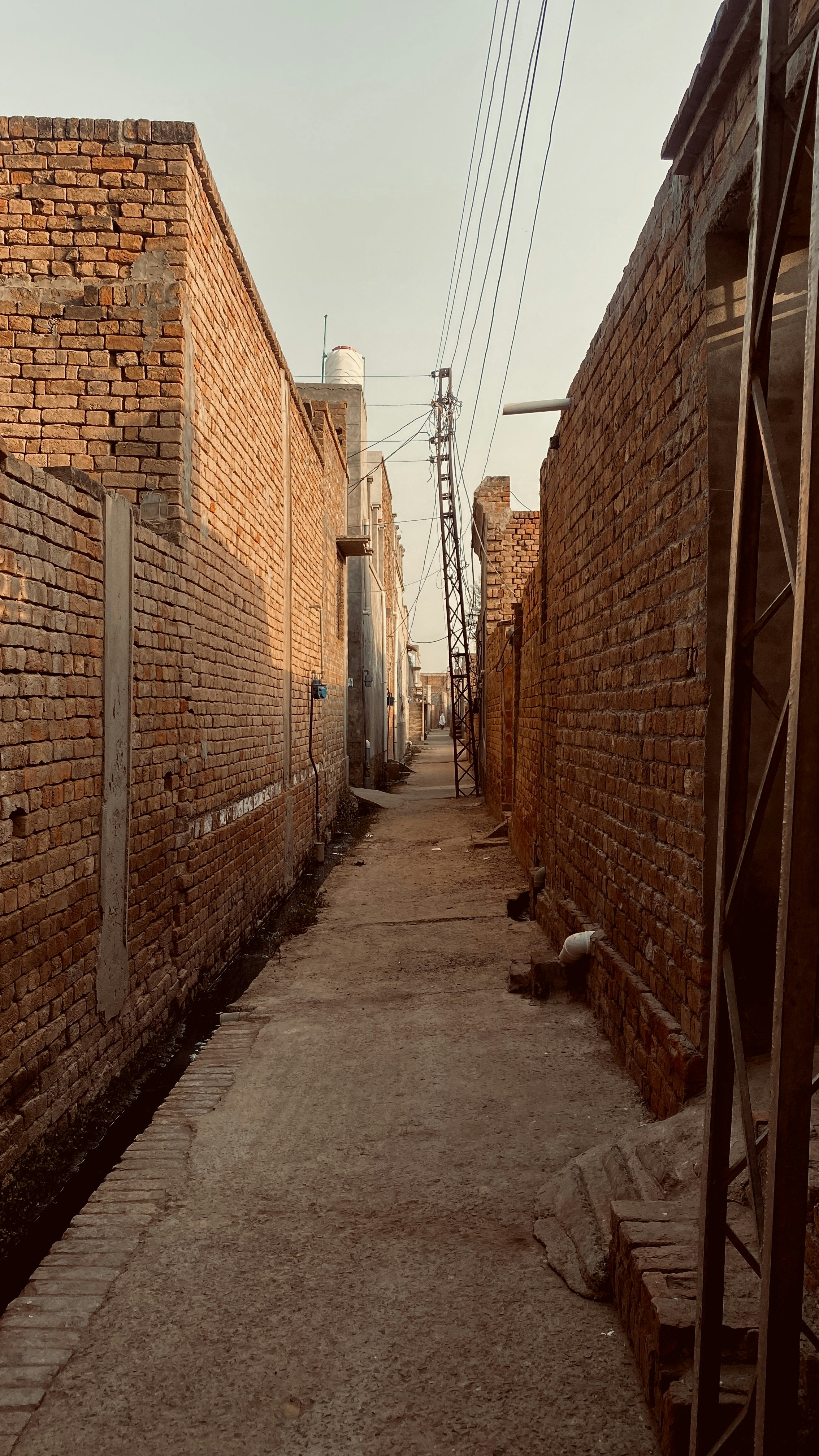 A narrow alley way with brick buildings and power lines photo – Free ...
