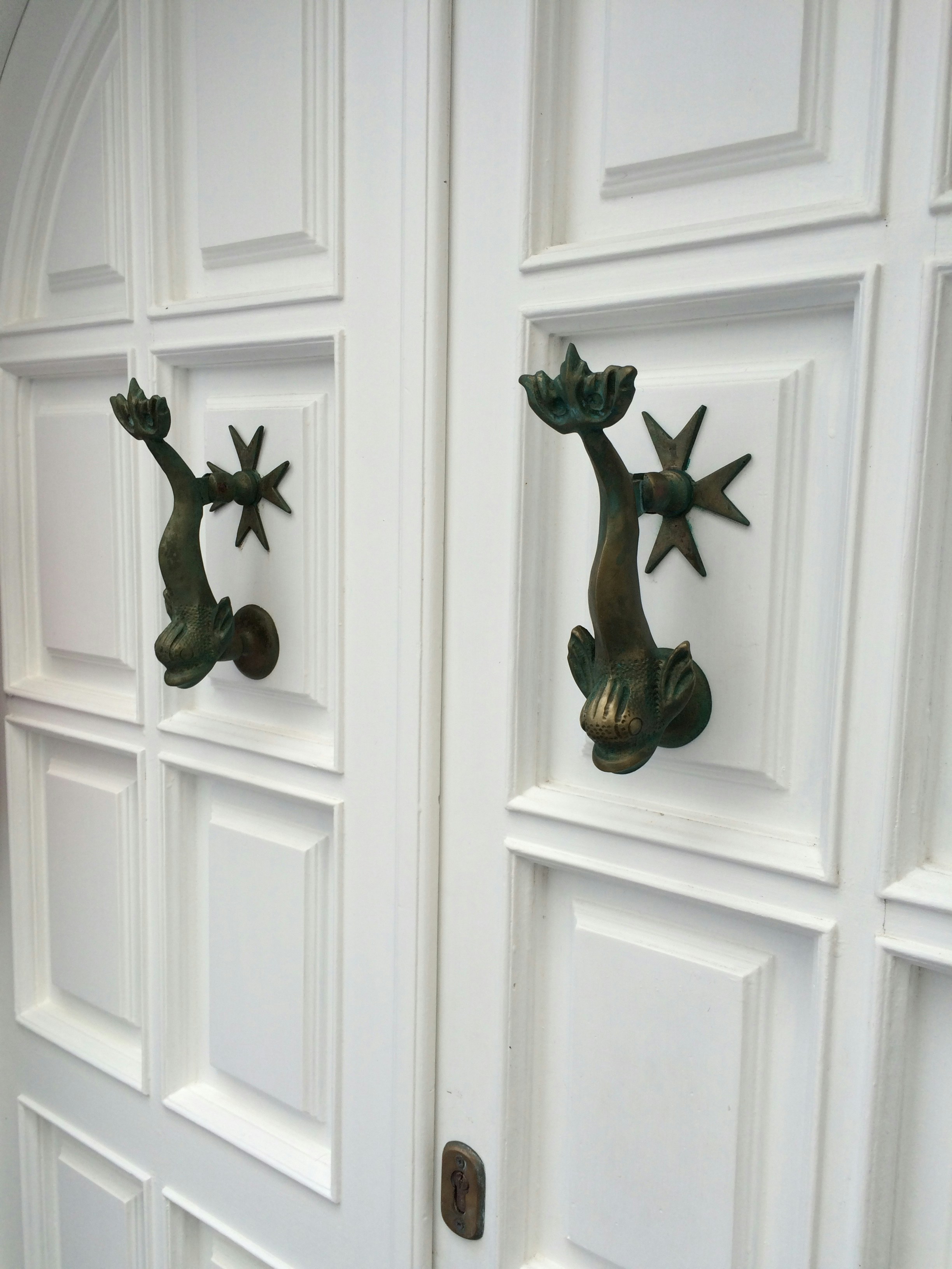 Bronze door-knocker duet on white paneled doors