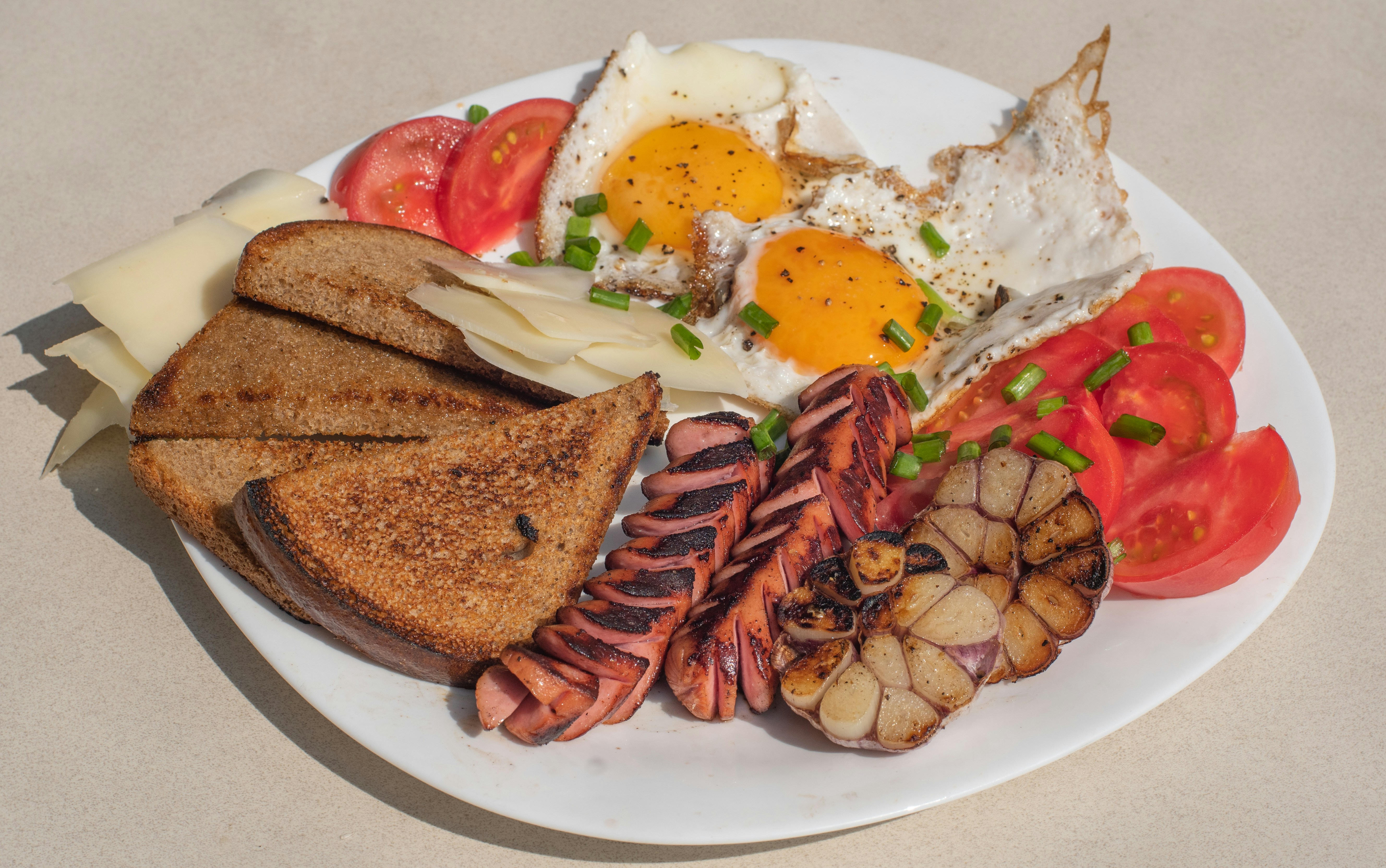 Two-Egg Sunrise on a Rustic Plate: Toasted Rye, Tomatoes, and Charred Sausage Slices