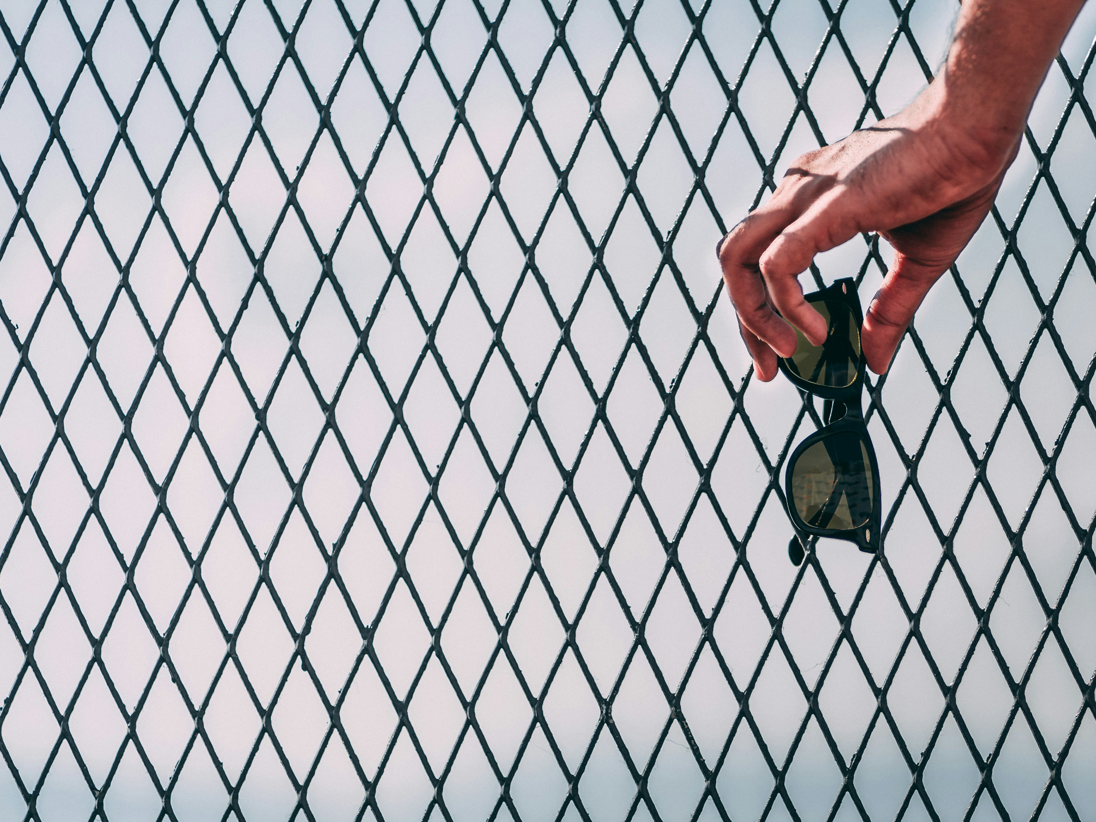 Grasp on the Grid: Sunglasses Dangle from a Hand over Diamond Mesh