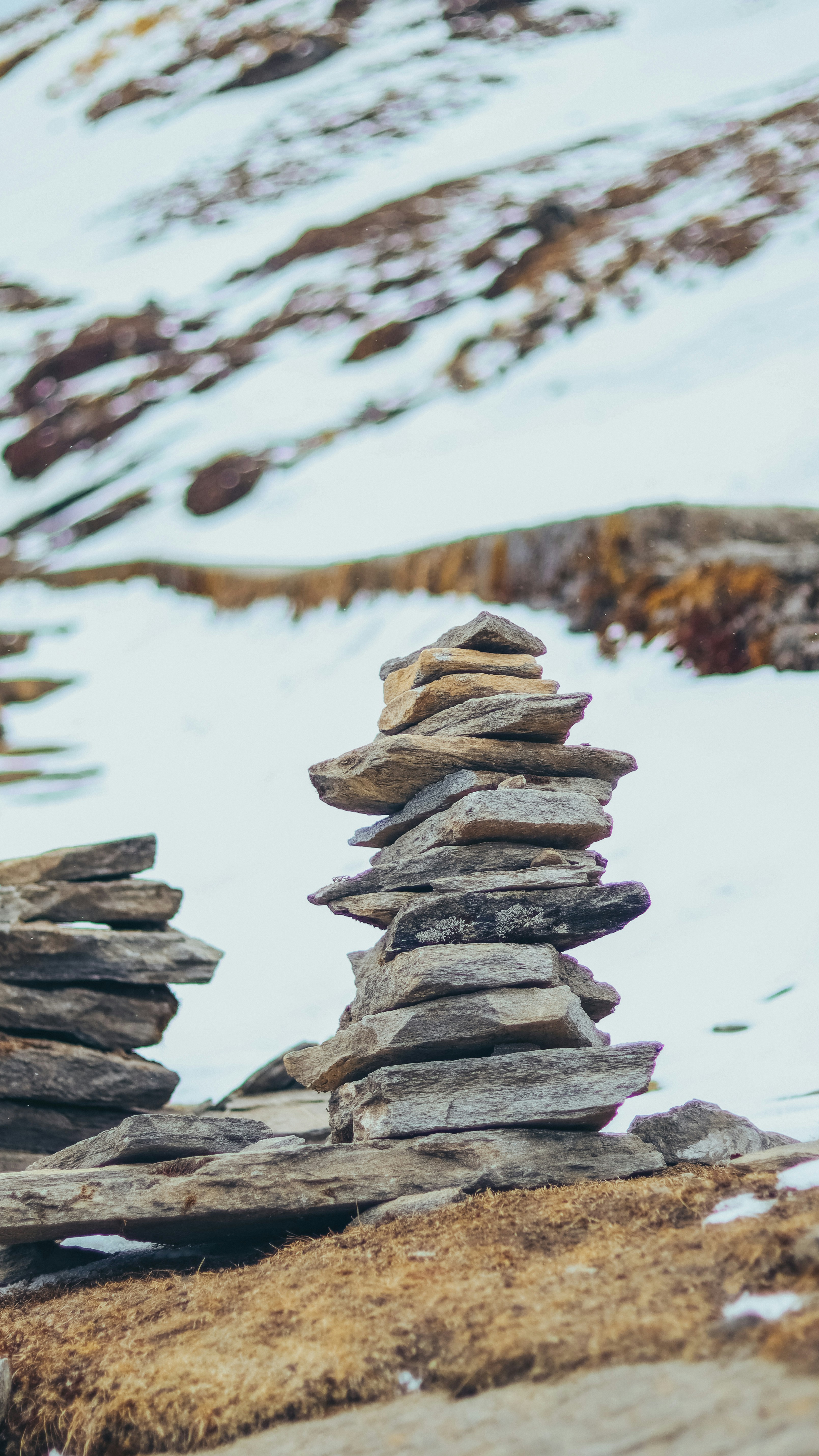 Stacked stones create a natural sculpture against a snowy backdrop, symbolizing harmony and balance in the wilderness.