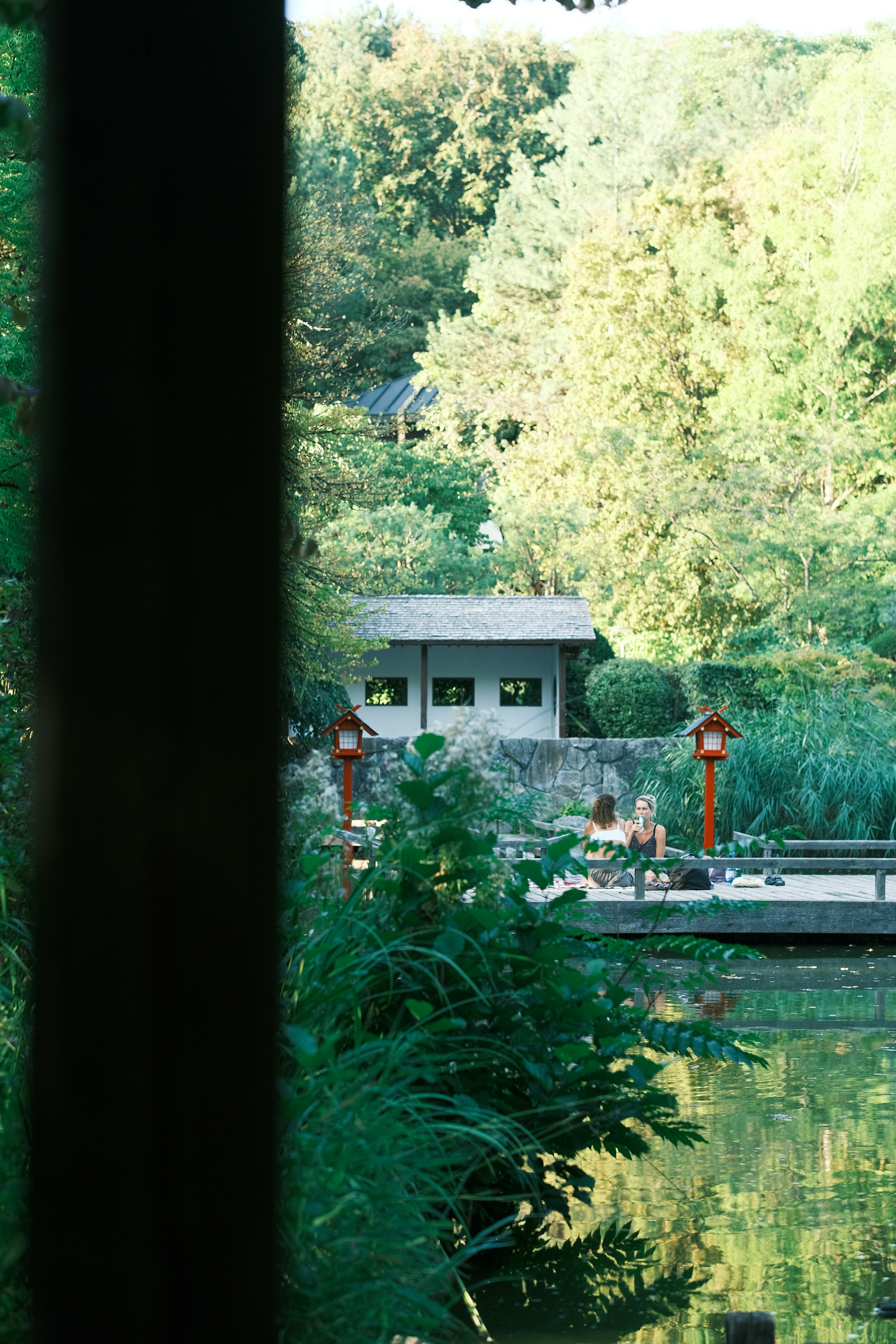 Hidden Oasis: People by the Pond Beneath Lantern Towers