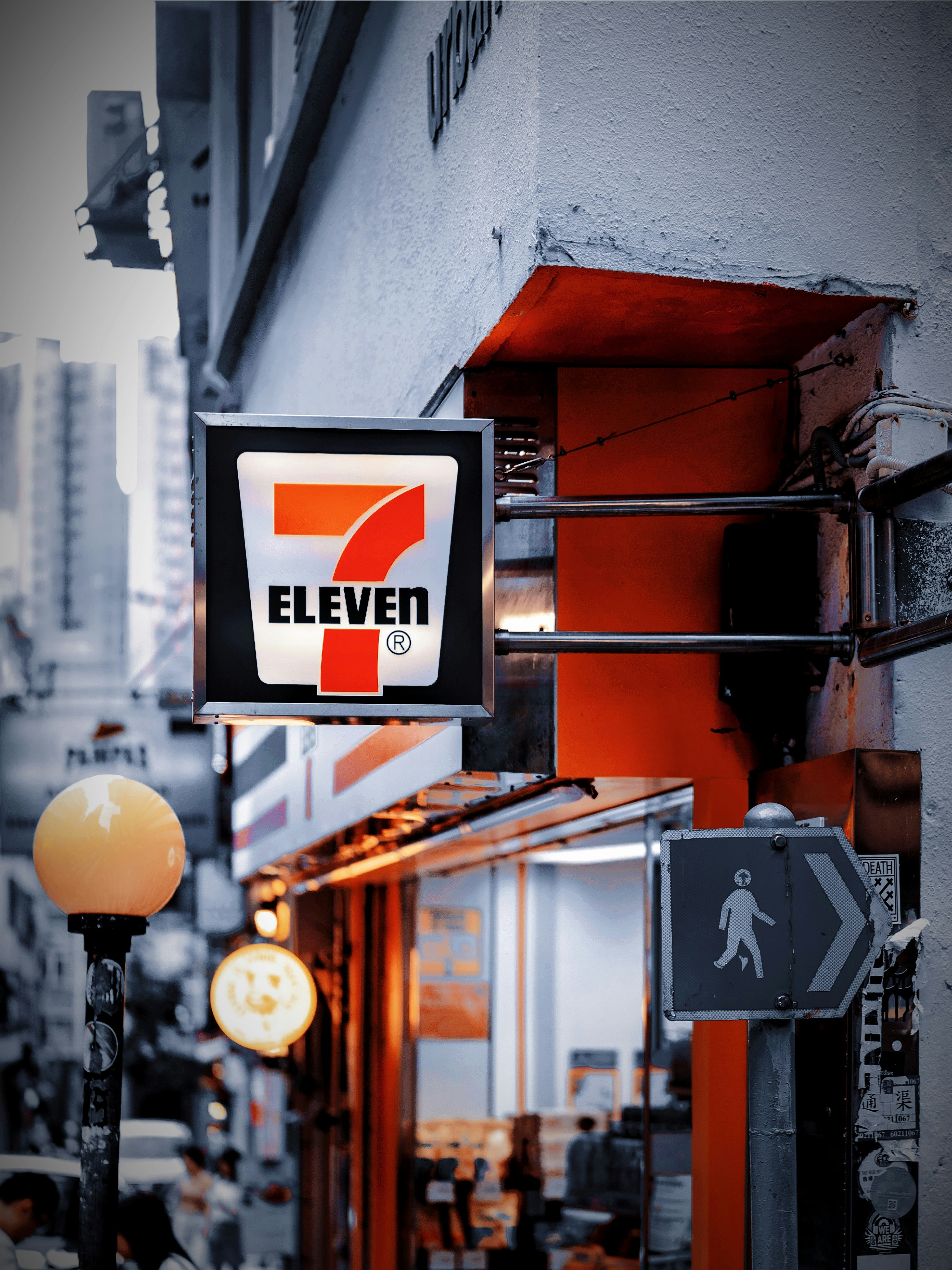 A 7 eleven sign hanging from the side of a building photo – Free Image ...