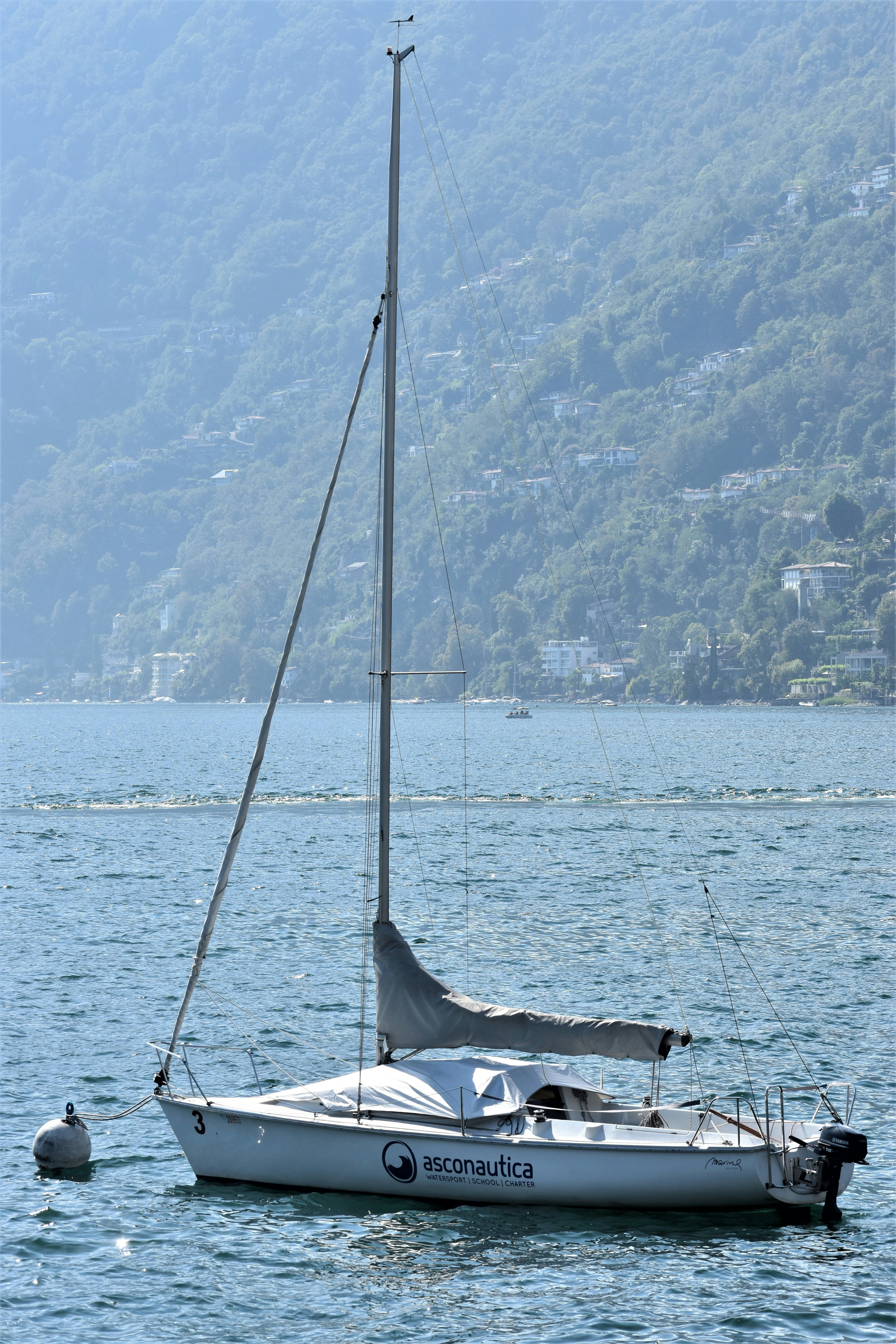 Anchored in Azure: A Sailboat Nestled Against a Mountain-Lined Bay