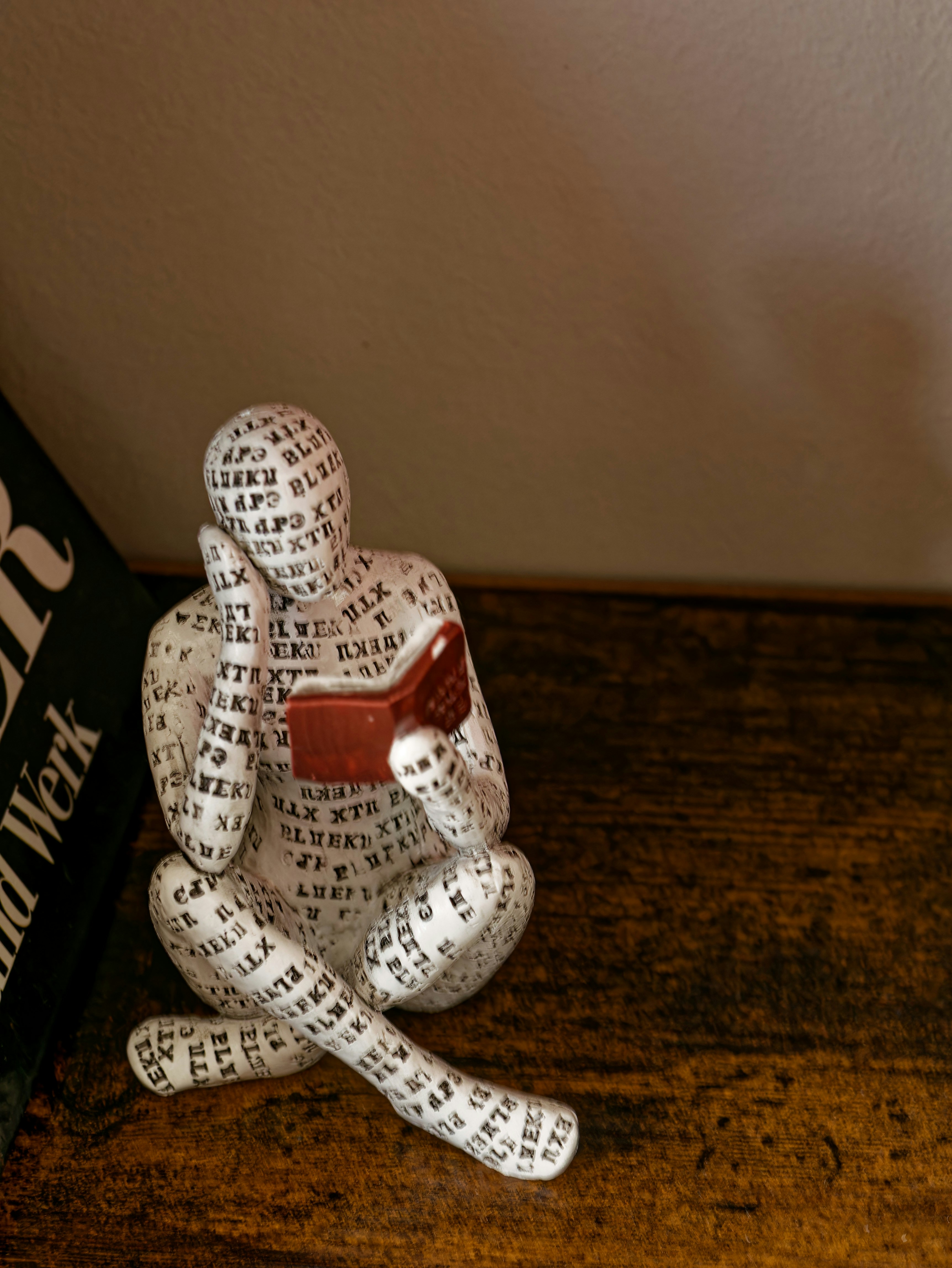 a statue of a person sitting on a table next to a book