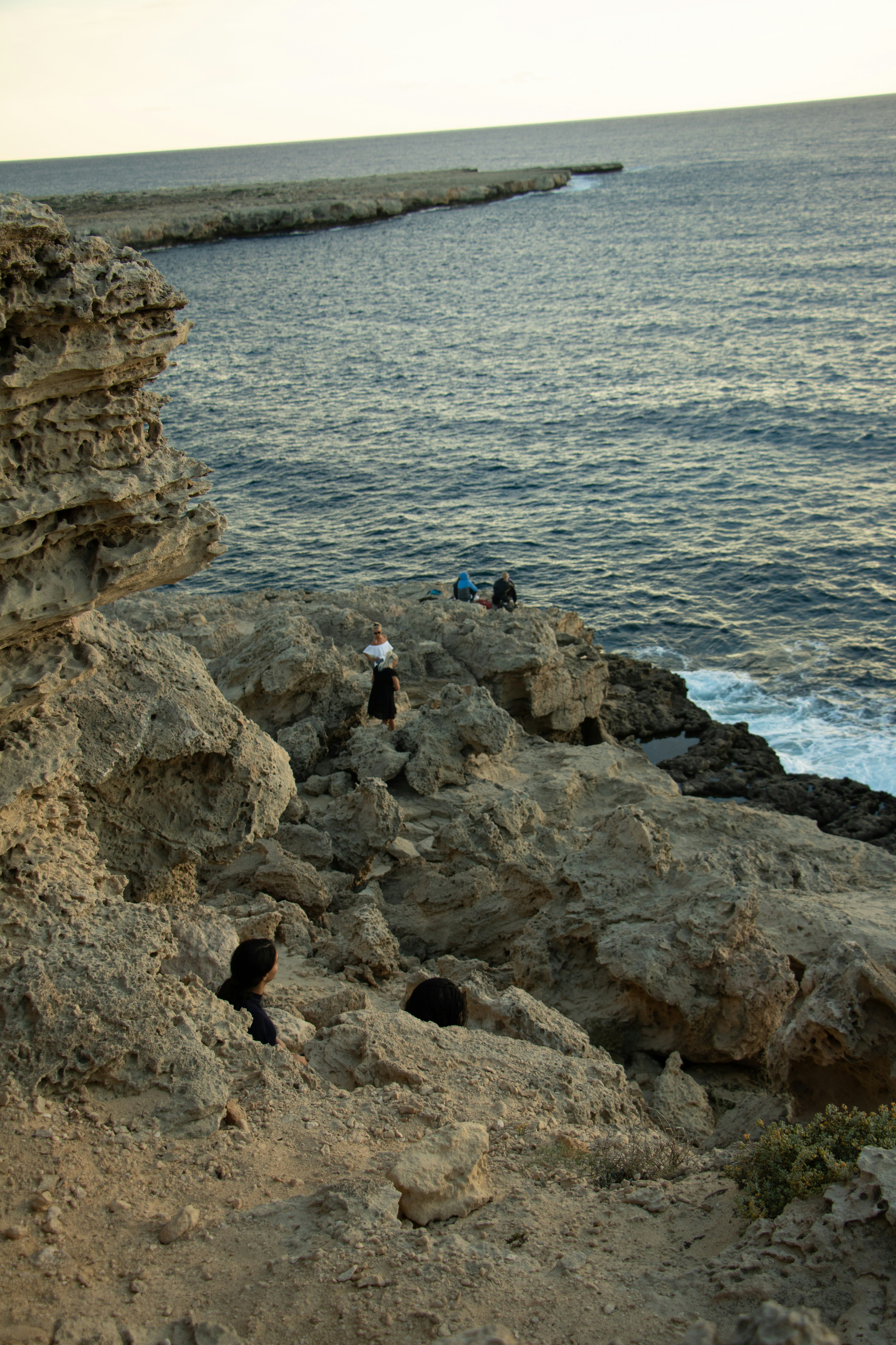 Craggy Edge: Figures Exploring a Limestone Seacliff at Dusk