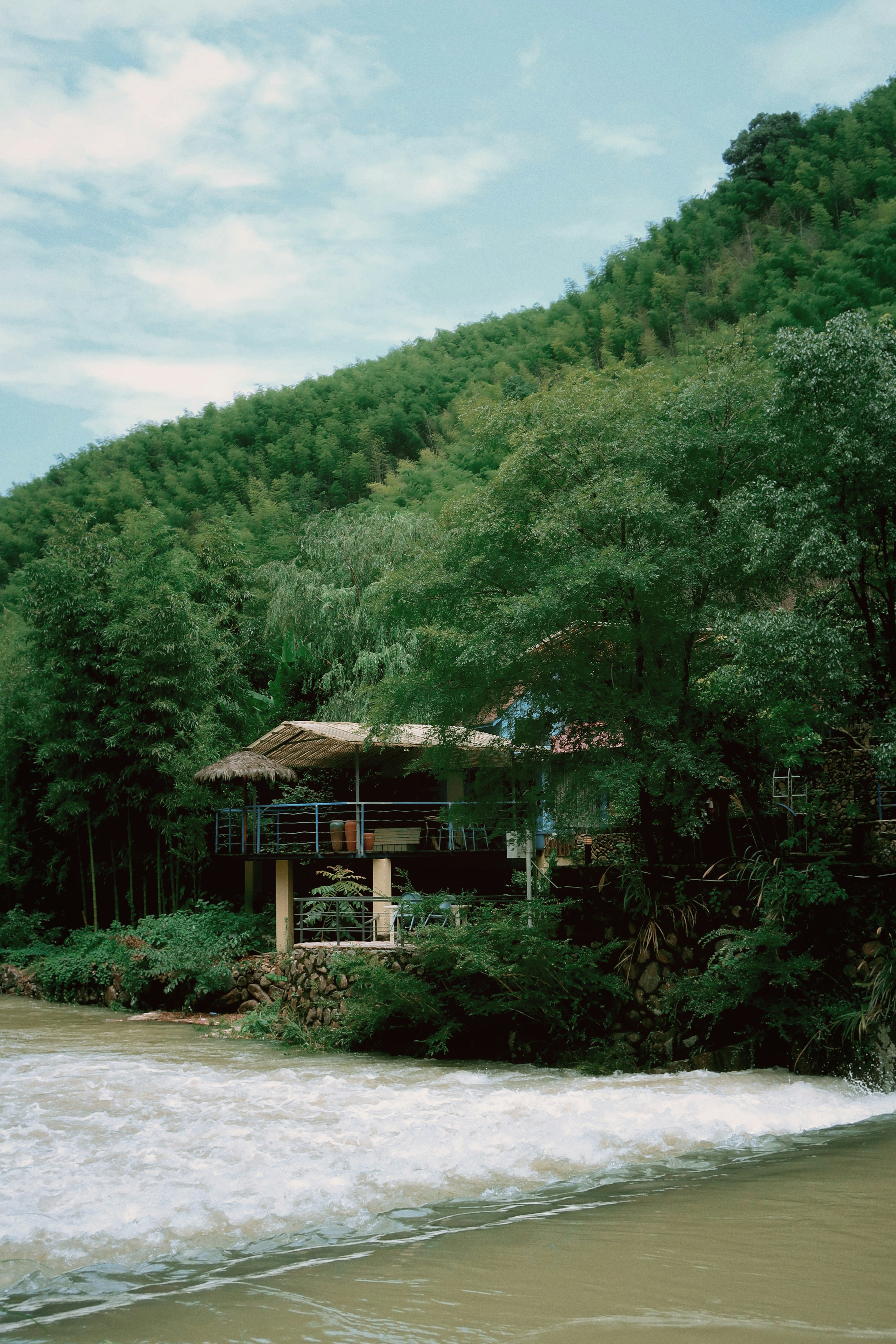 Thatched Riverside Retreat Framed by Verdant Slopes