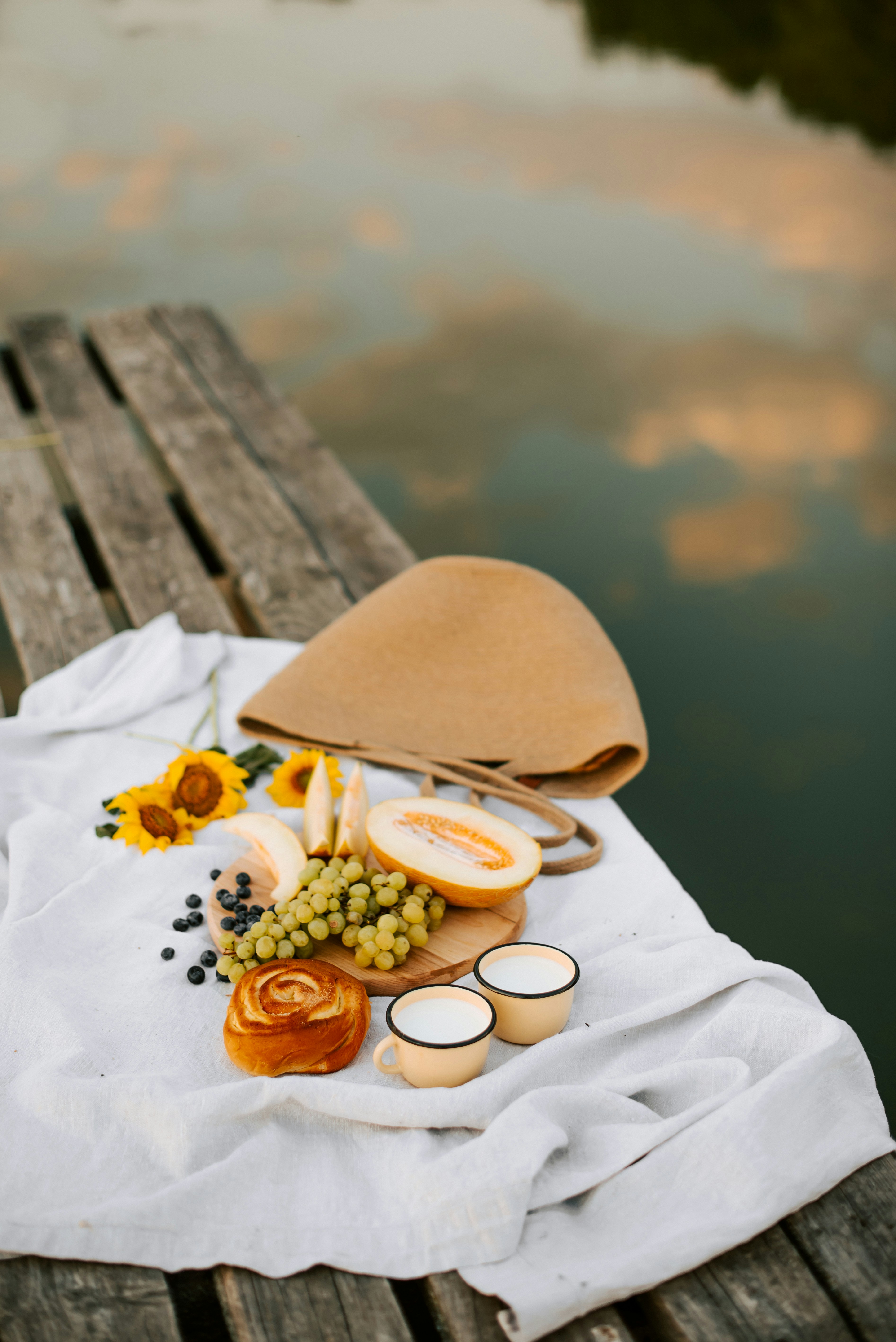 Riverside Spread: Croissant, Grapes, and Sunflowers on Weathered Planks