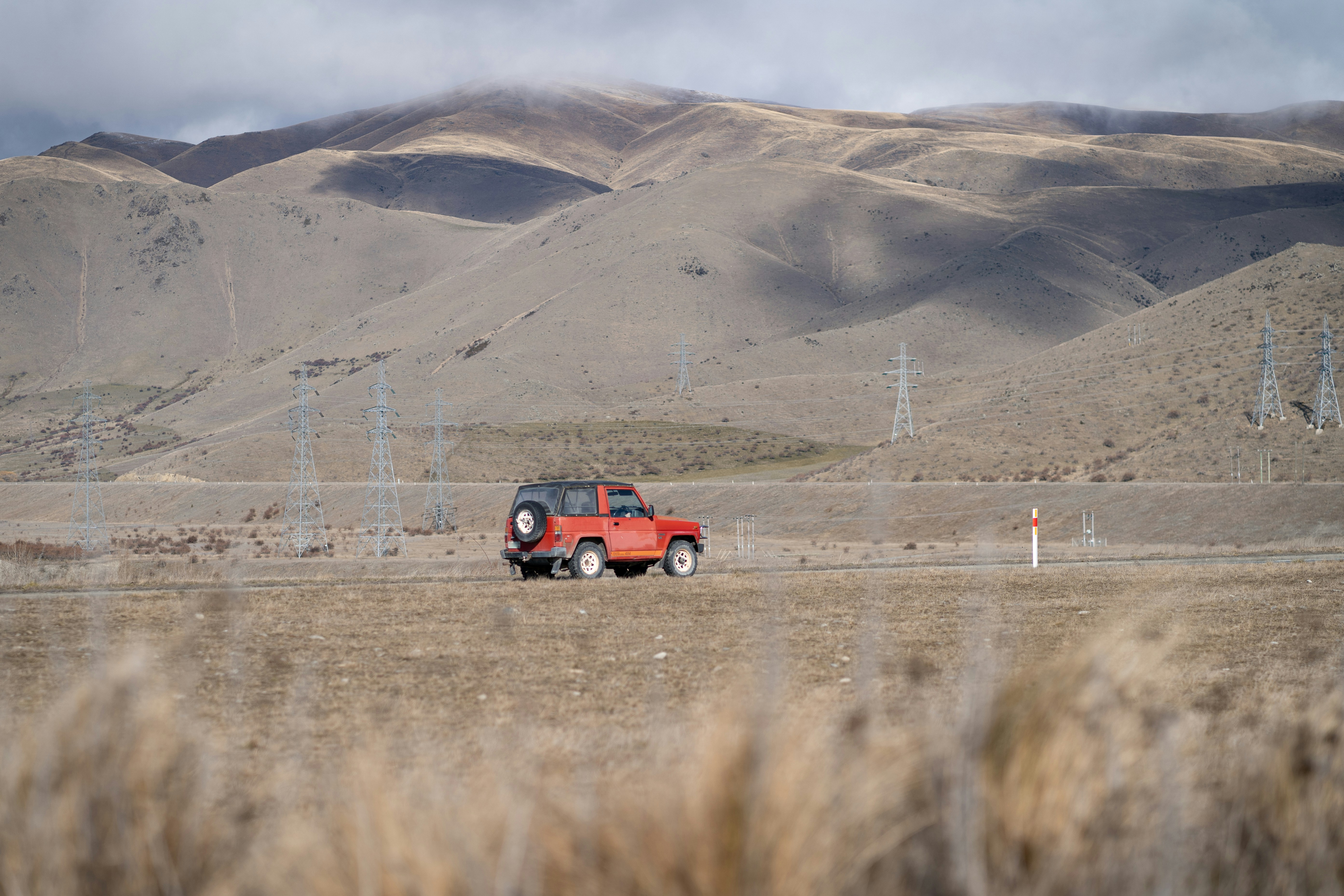 Red Jeep Traversing an Arid Plain Beneath Distant Hills