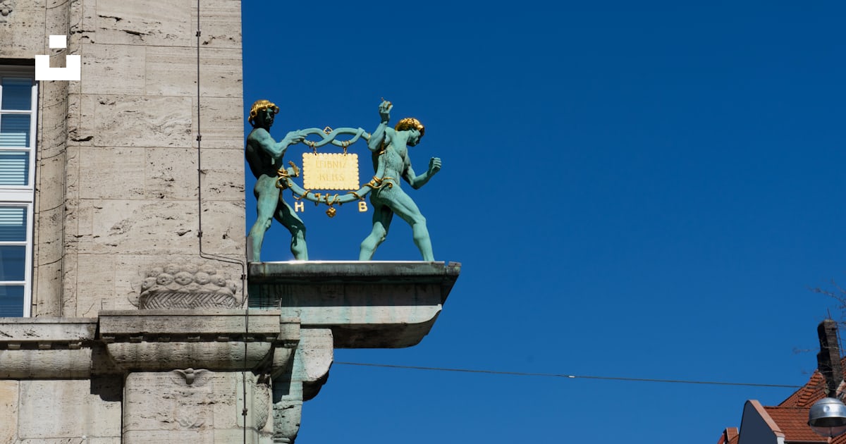 Una Estatua De Dos Hombres Sosteniendo Un Cartel En La Parte Superior