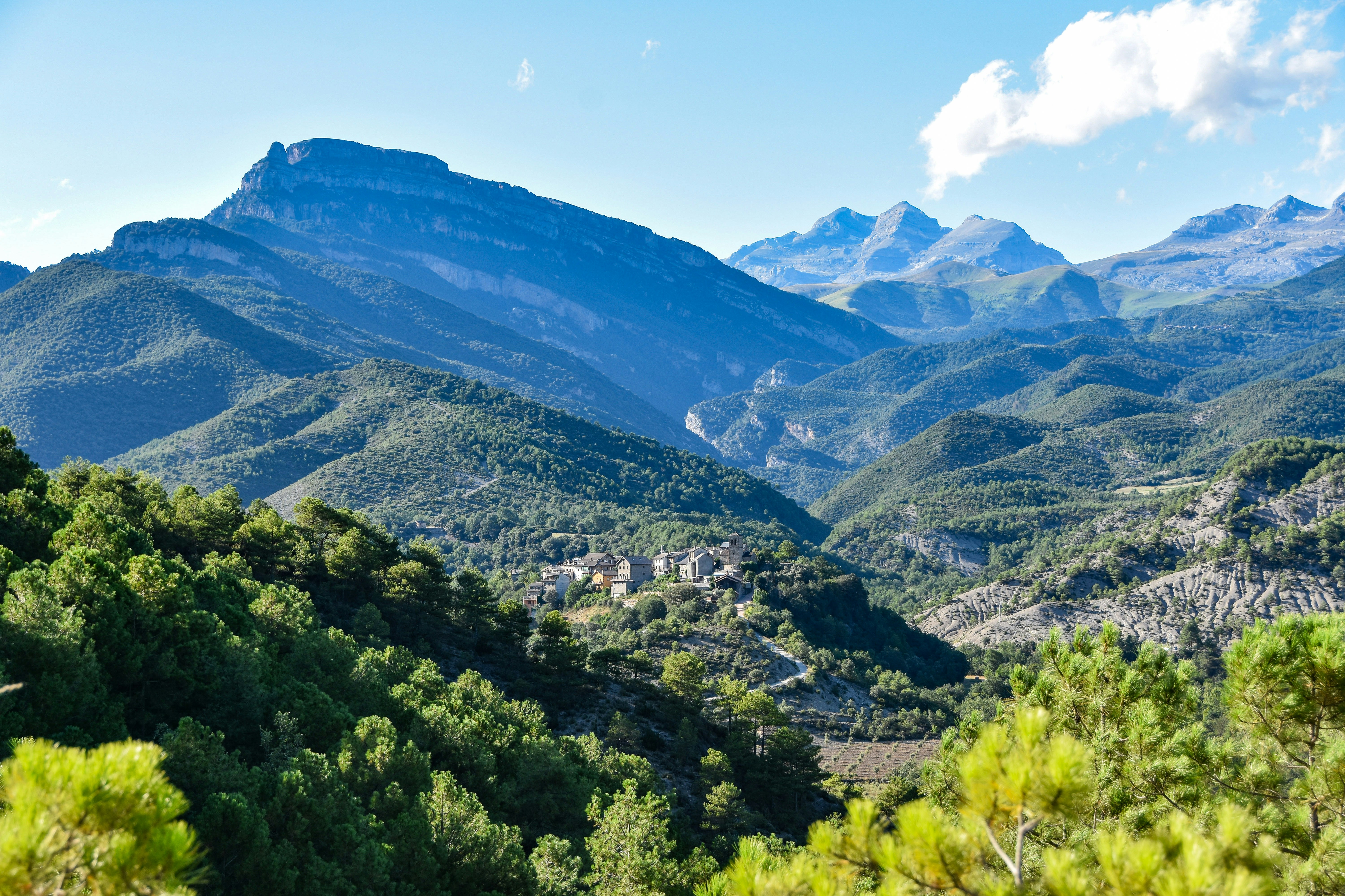 Mountain range with lush green valleys under a clear blue sky.