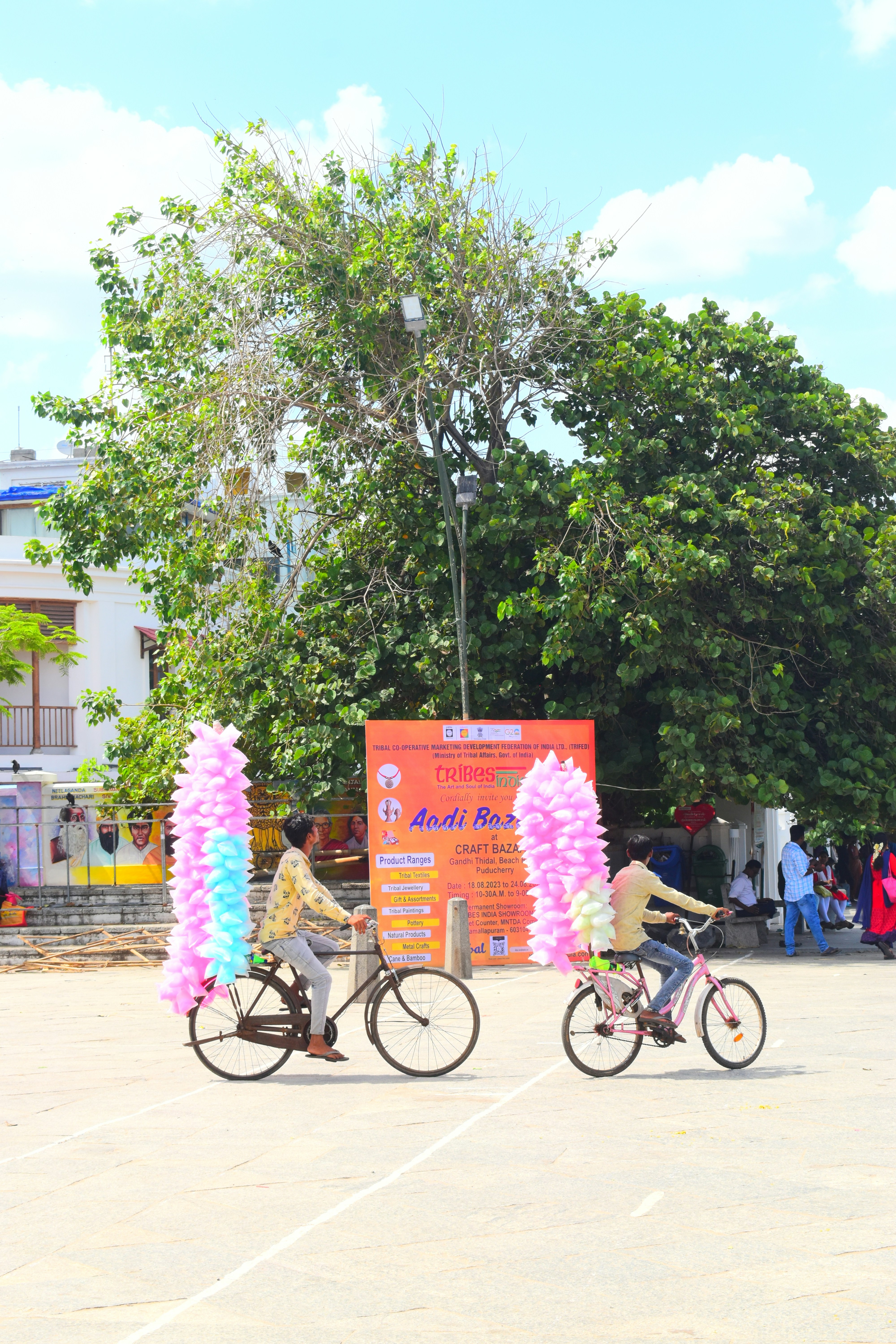 Candy-Towered Cyclists at a Sunlit Town Fair