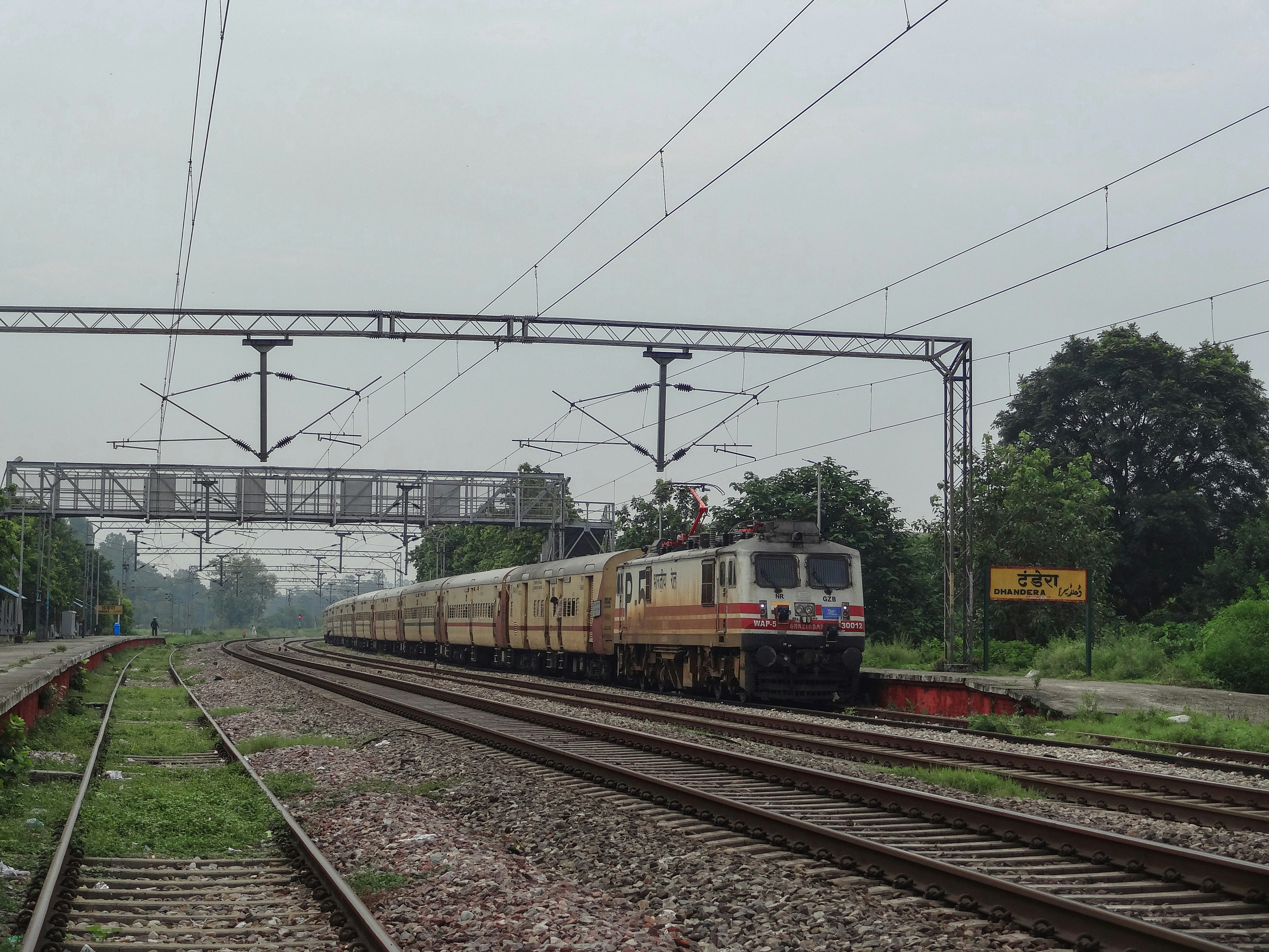A train traveling down train tracks next to a forest photo – Free ...