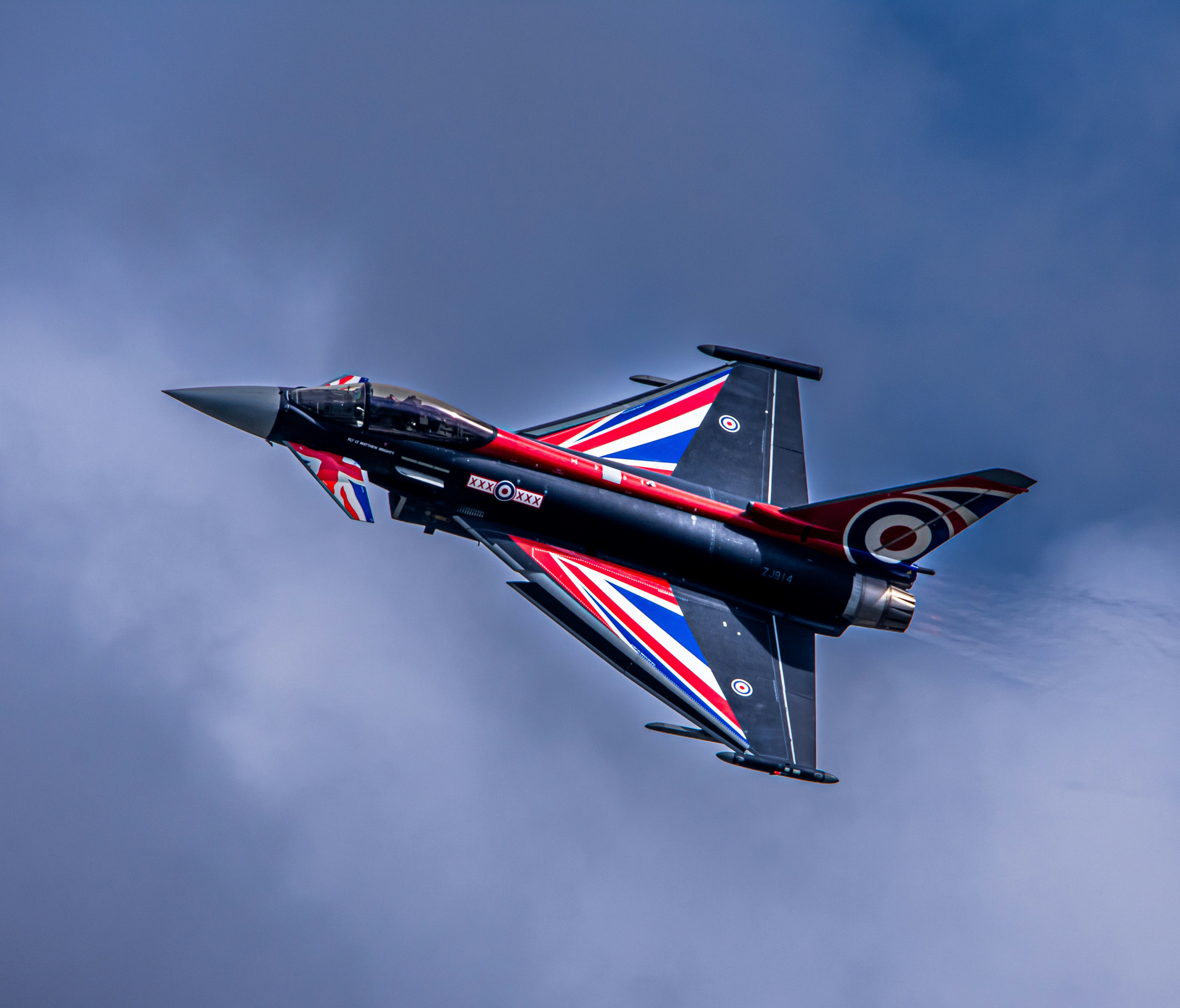 A red, white and blue jet flying through a cloudy sky photo – Free ...