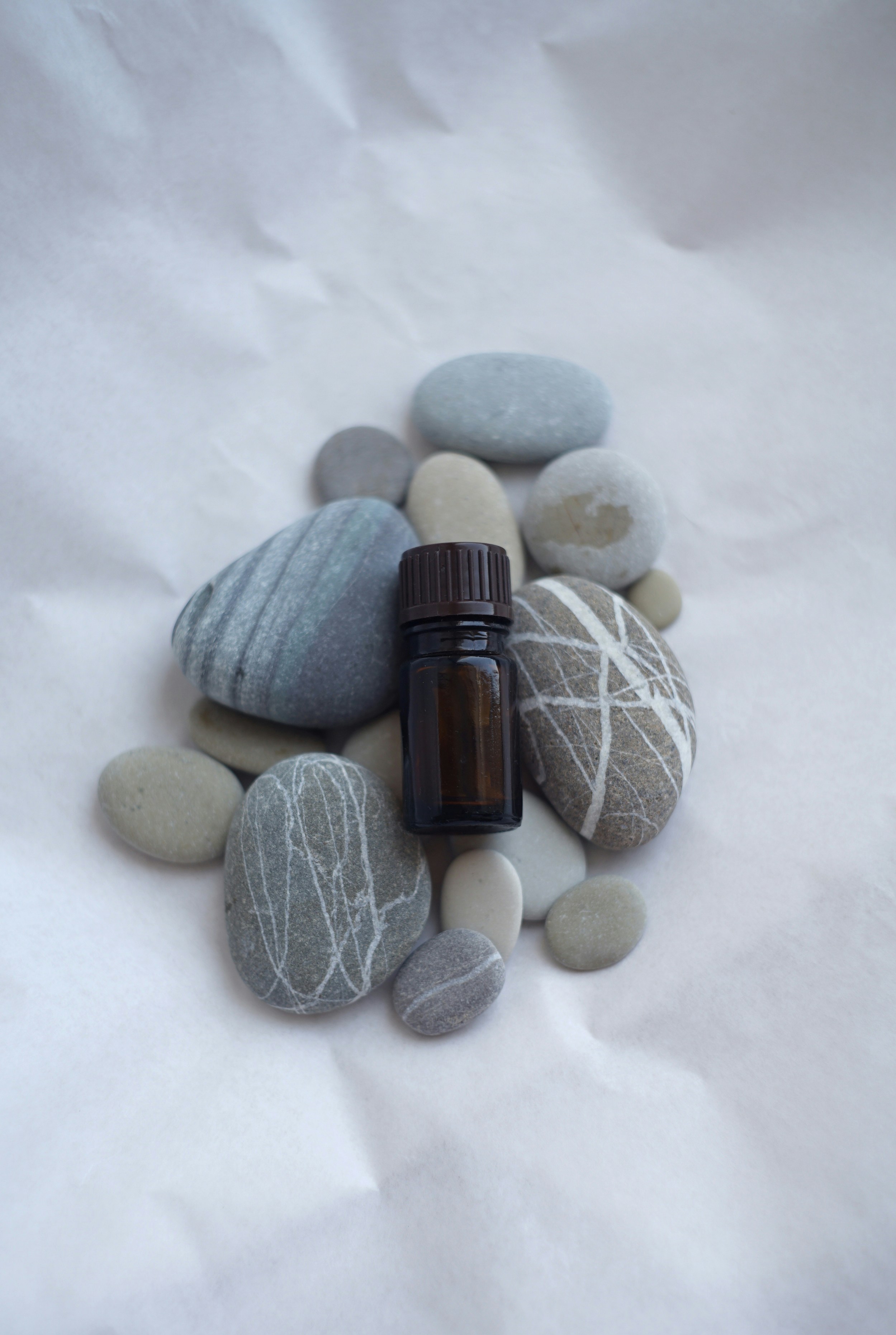 A bottle of essential oil sitting on a pile of rocks photo – Free ...