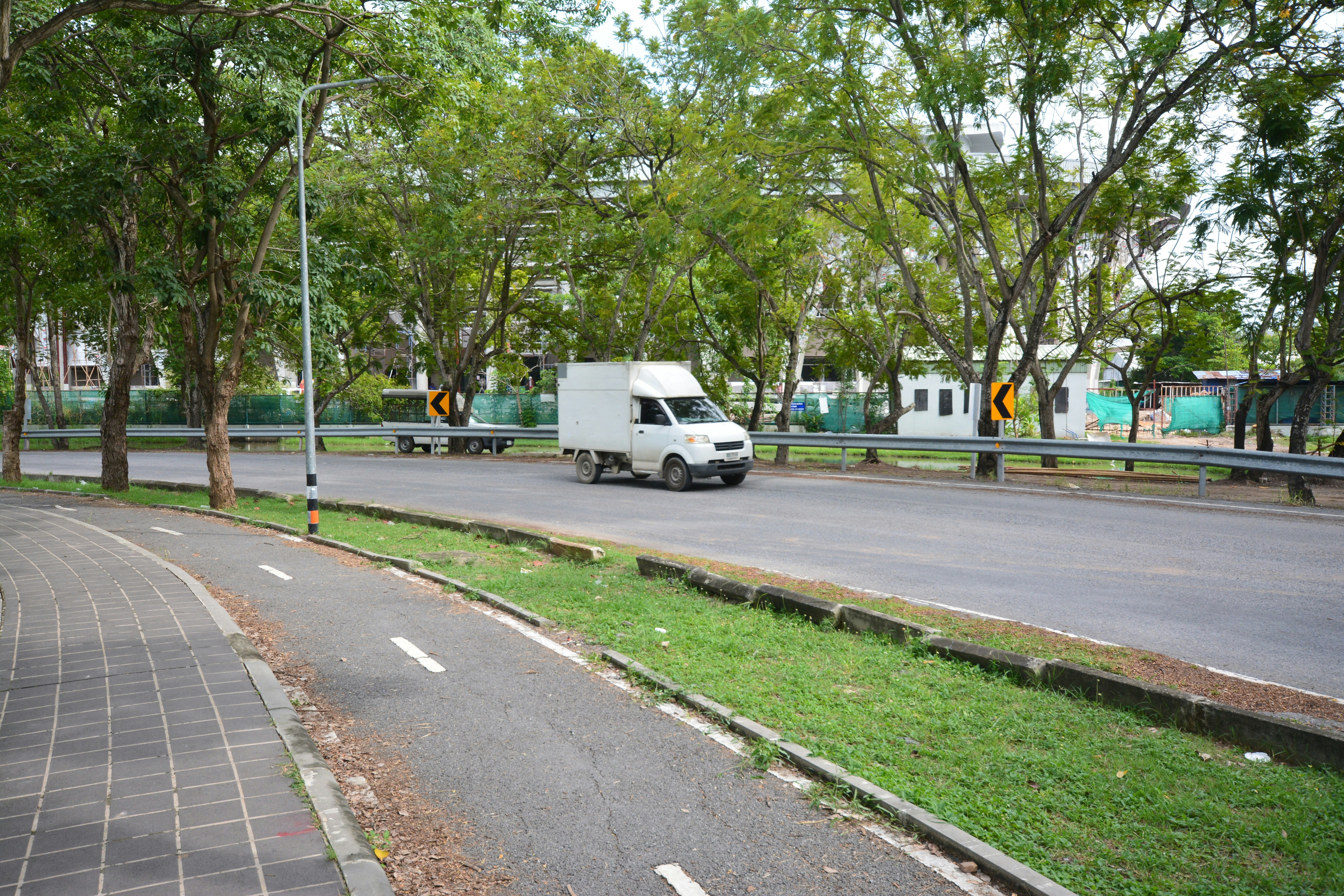a white truck driving down a street next to a park