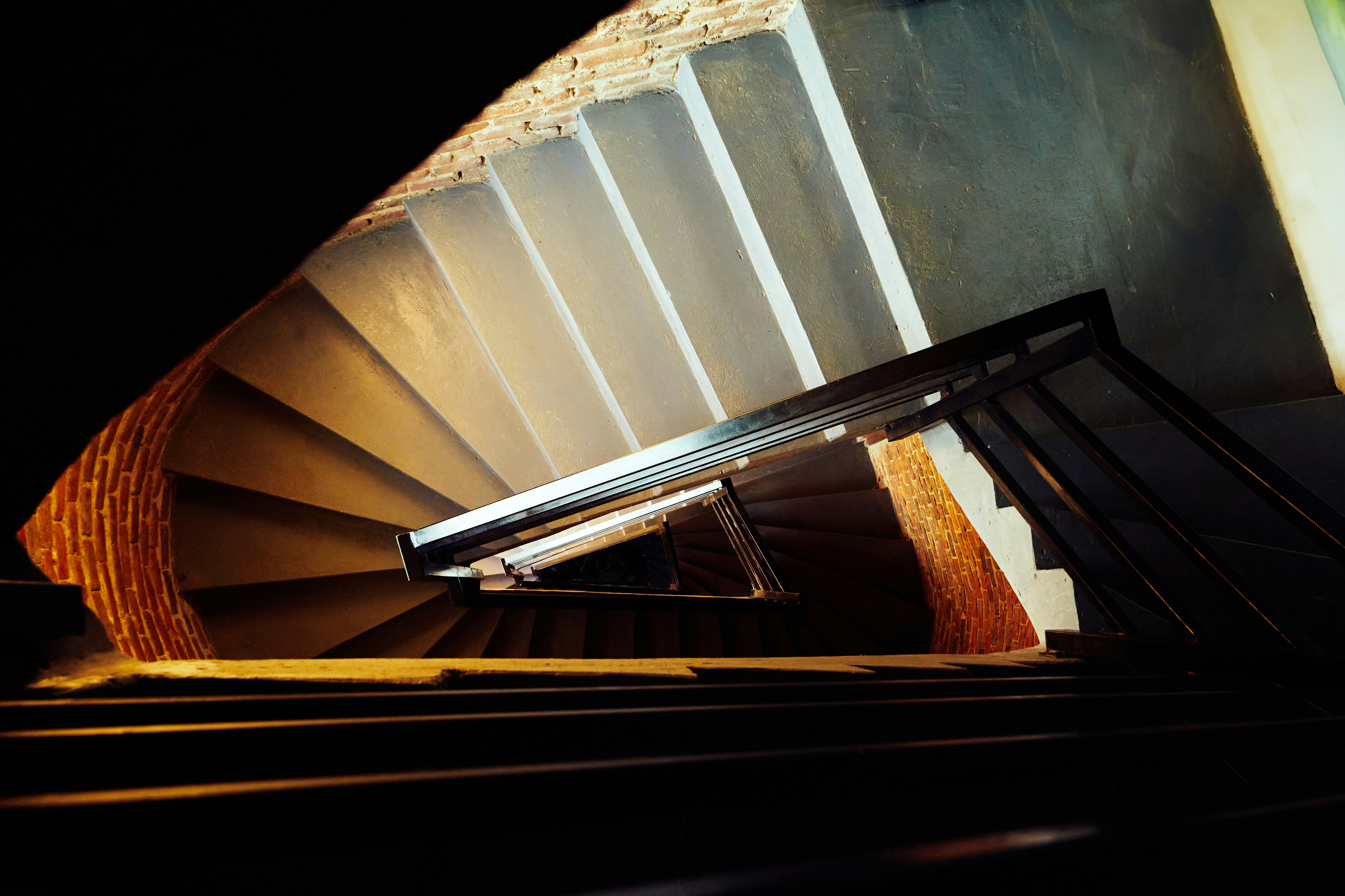 Spiral staircase with light streaming through, casting shadows on the steps.
