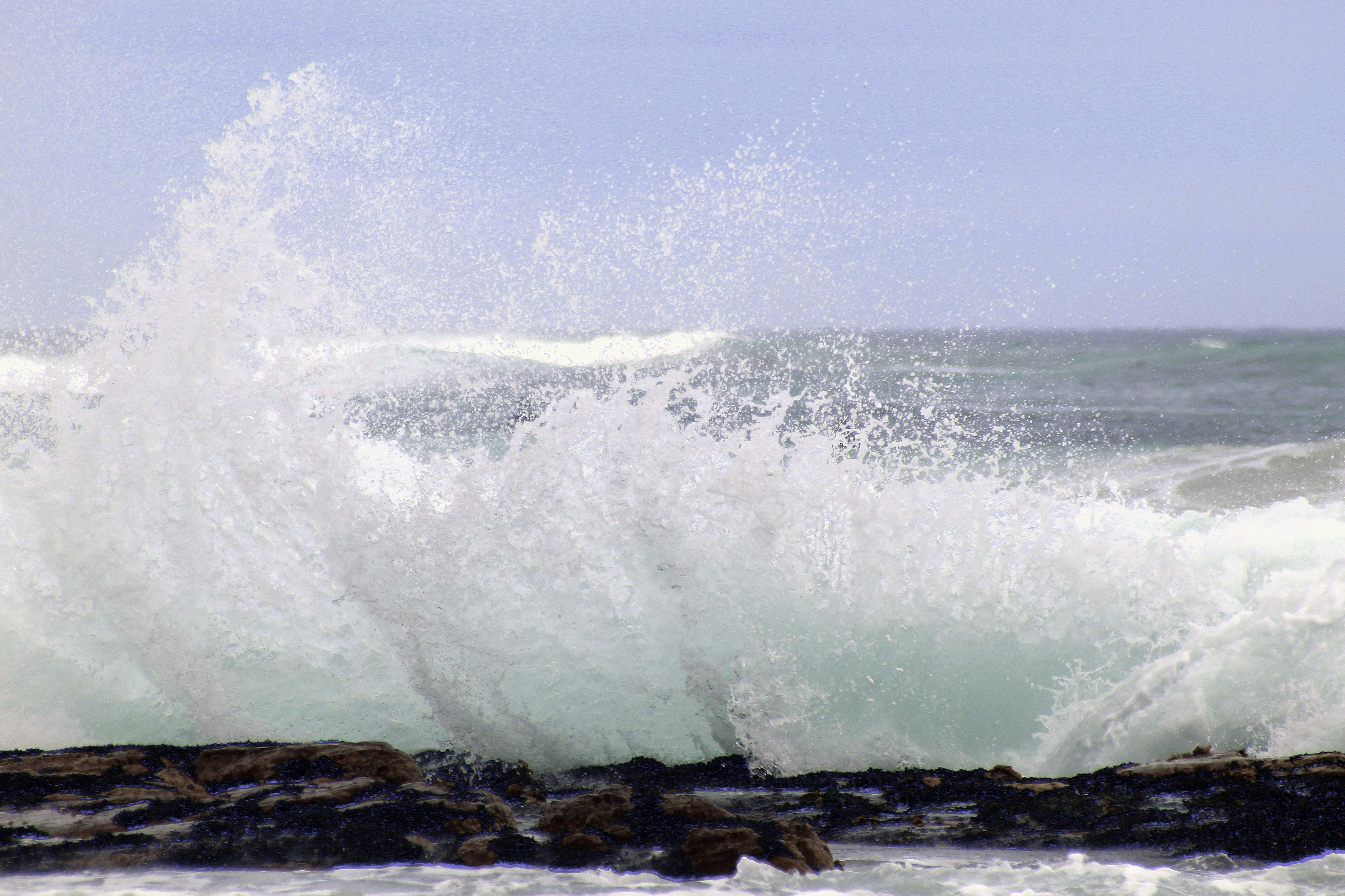 A large wave crashing over a rocky shore photo – Free Nature Image on ...