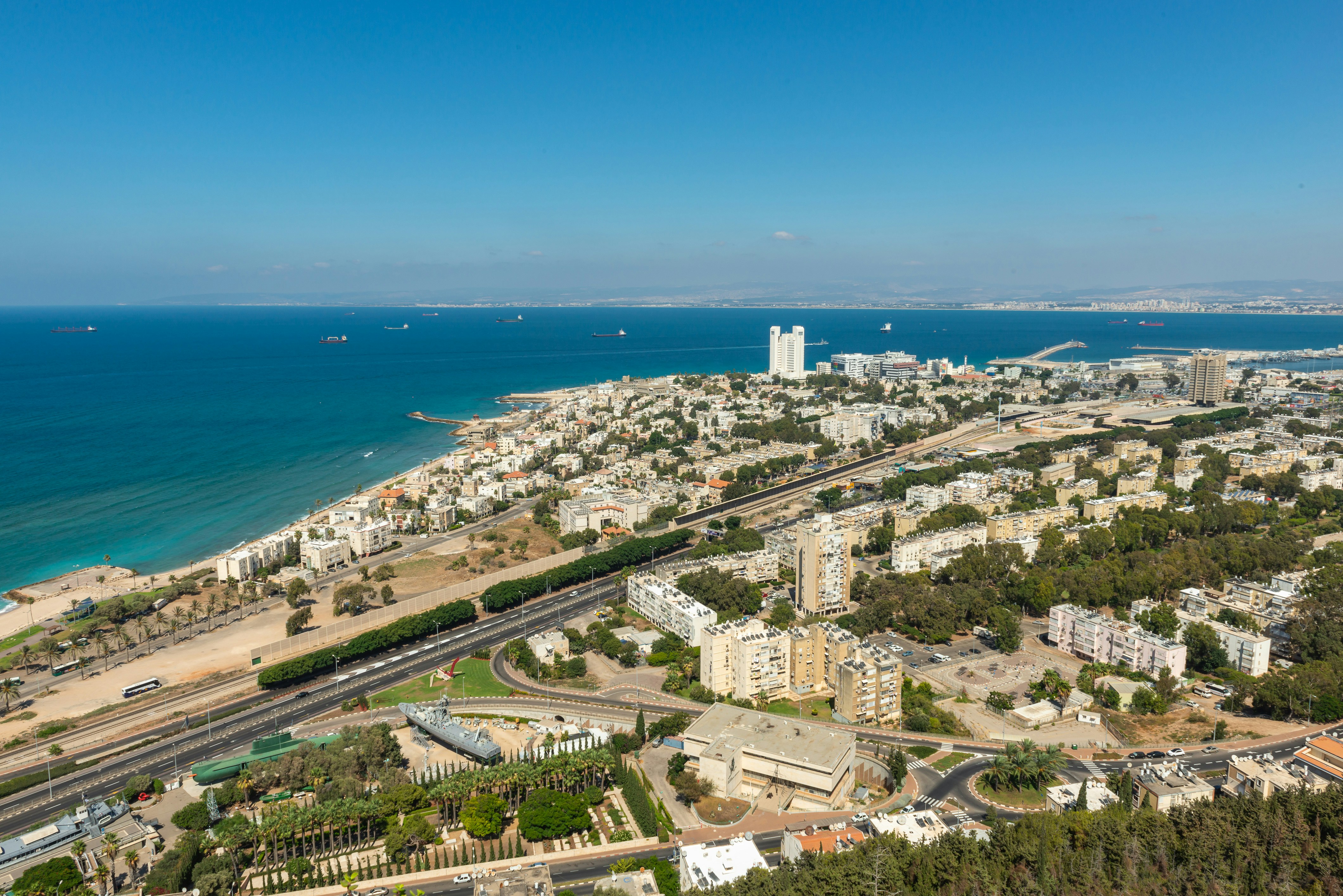 Aerial view showcasing a vibrant coastal city with lush greenery, sandy beaches, and a serene blue sea. The landscape highlights the harmonious blend of urban development and natural beauty.