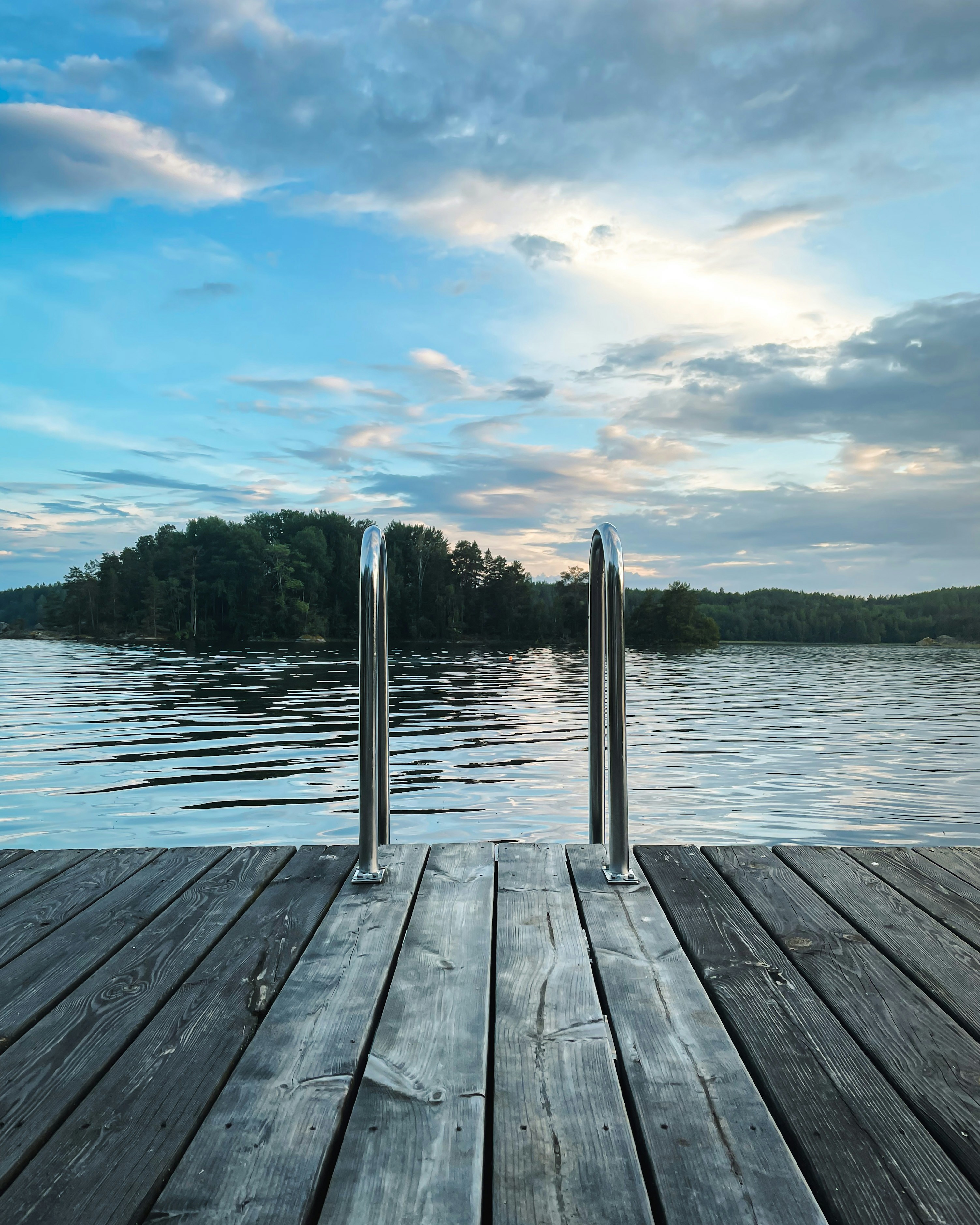 A wooden dock with two metal poles sticking out of the water photo ...
