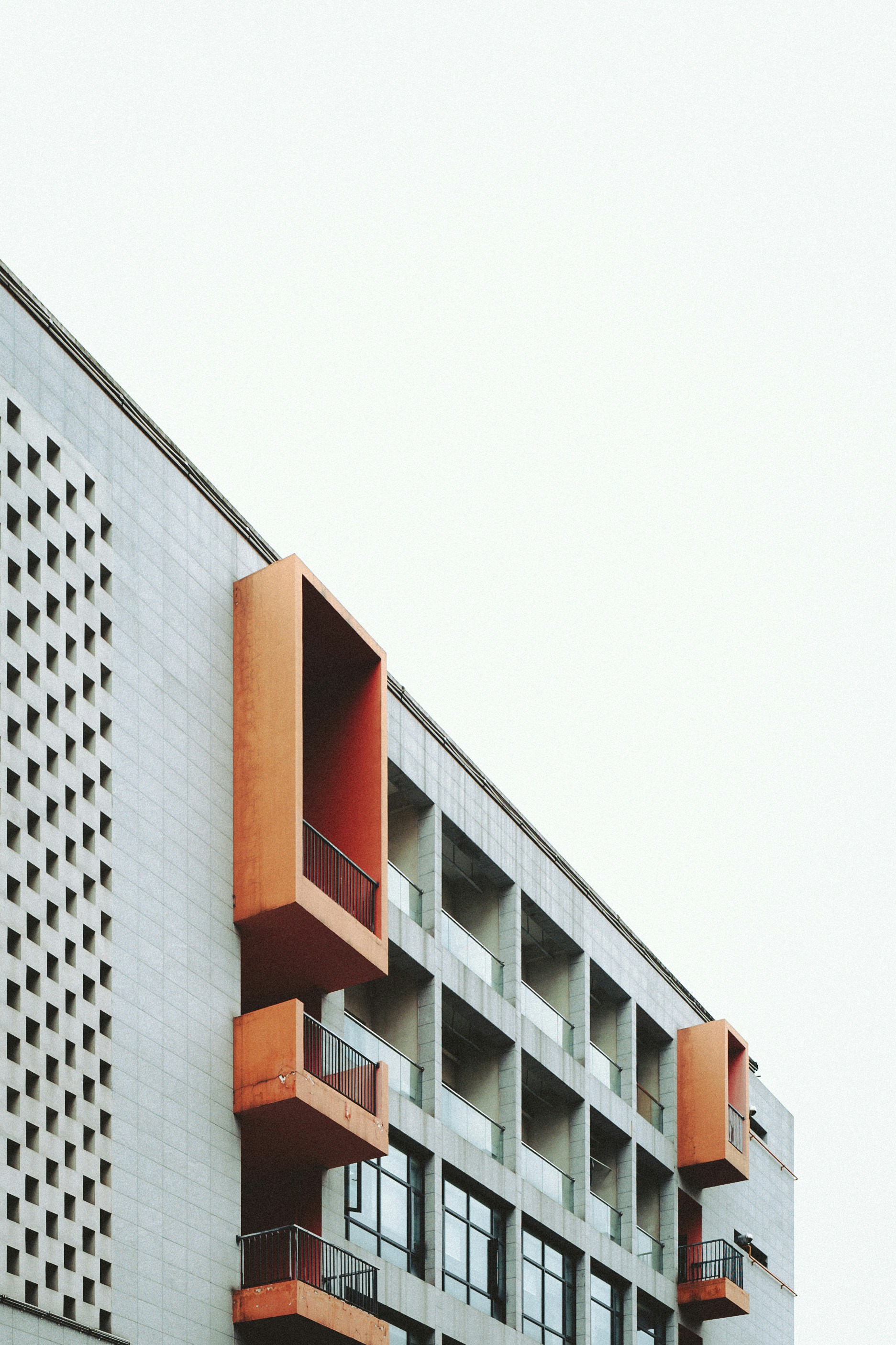 Cantilevered Orange Balconies Slice Through a Geometric Facade