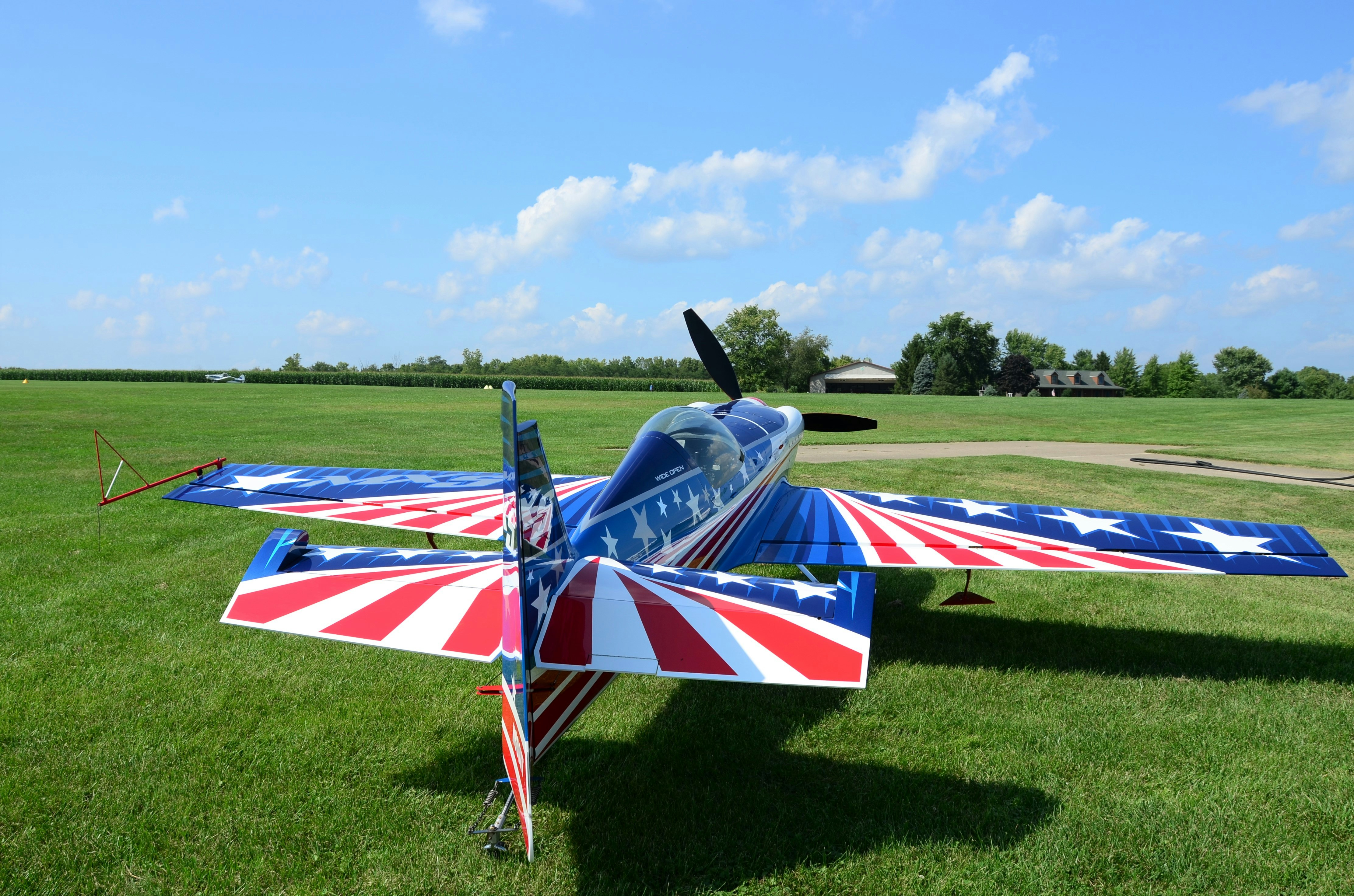 A red, white and blue plane is parked in the grass photo – Free Airport ...