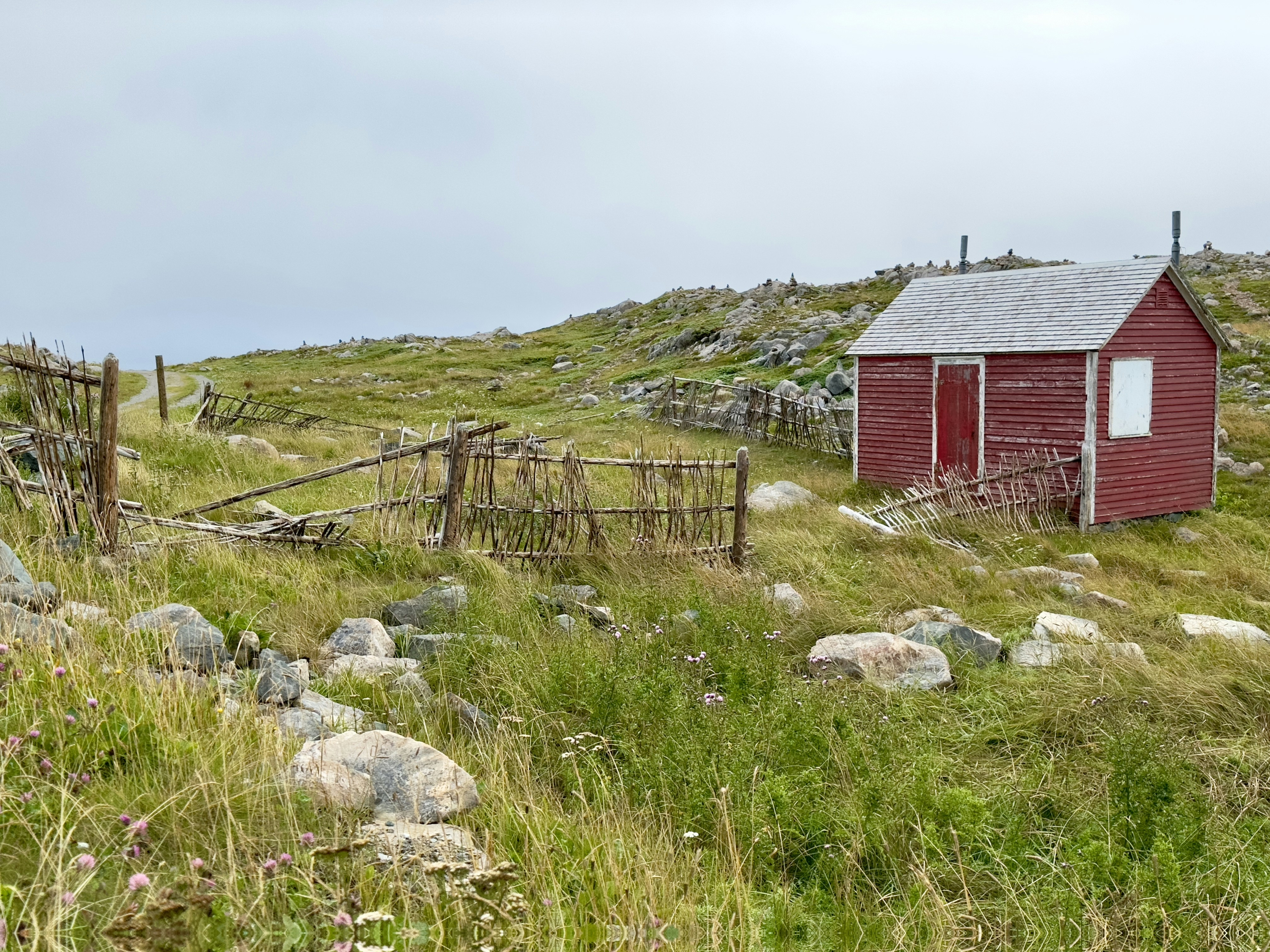 A small red building sitting on top of a lush green hillside photo ...