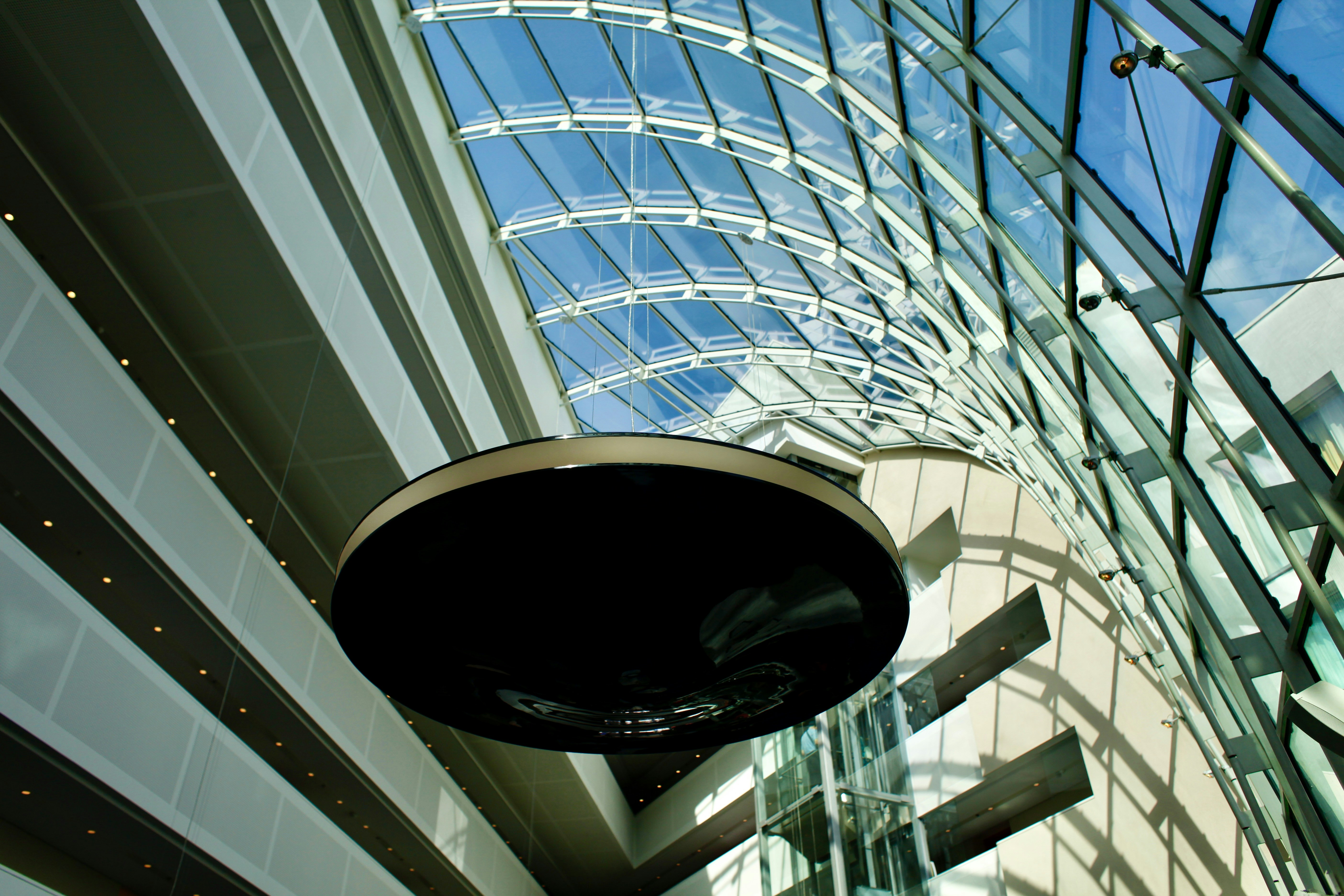 Floating Black Disk Over a Glass-Curved Atrium